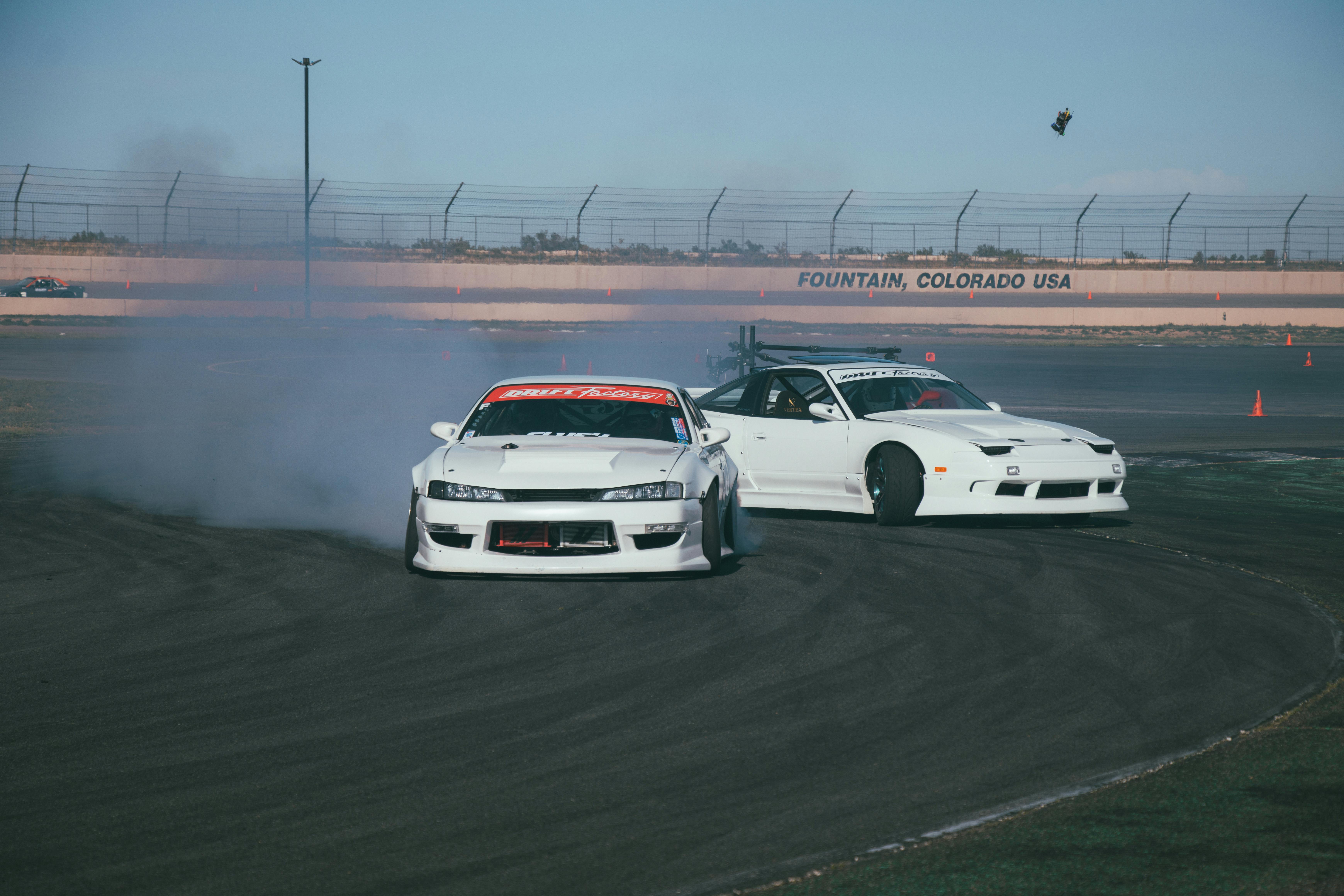 Two cars drifting on a track with smoke coming out of them · Free Stock ...