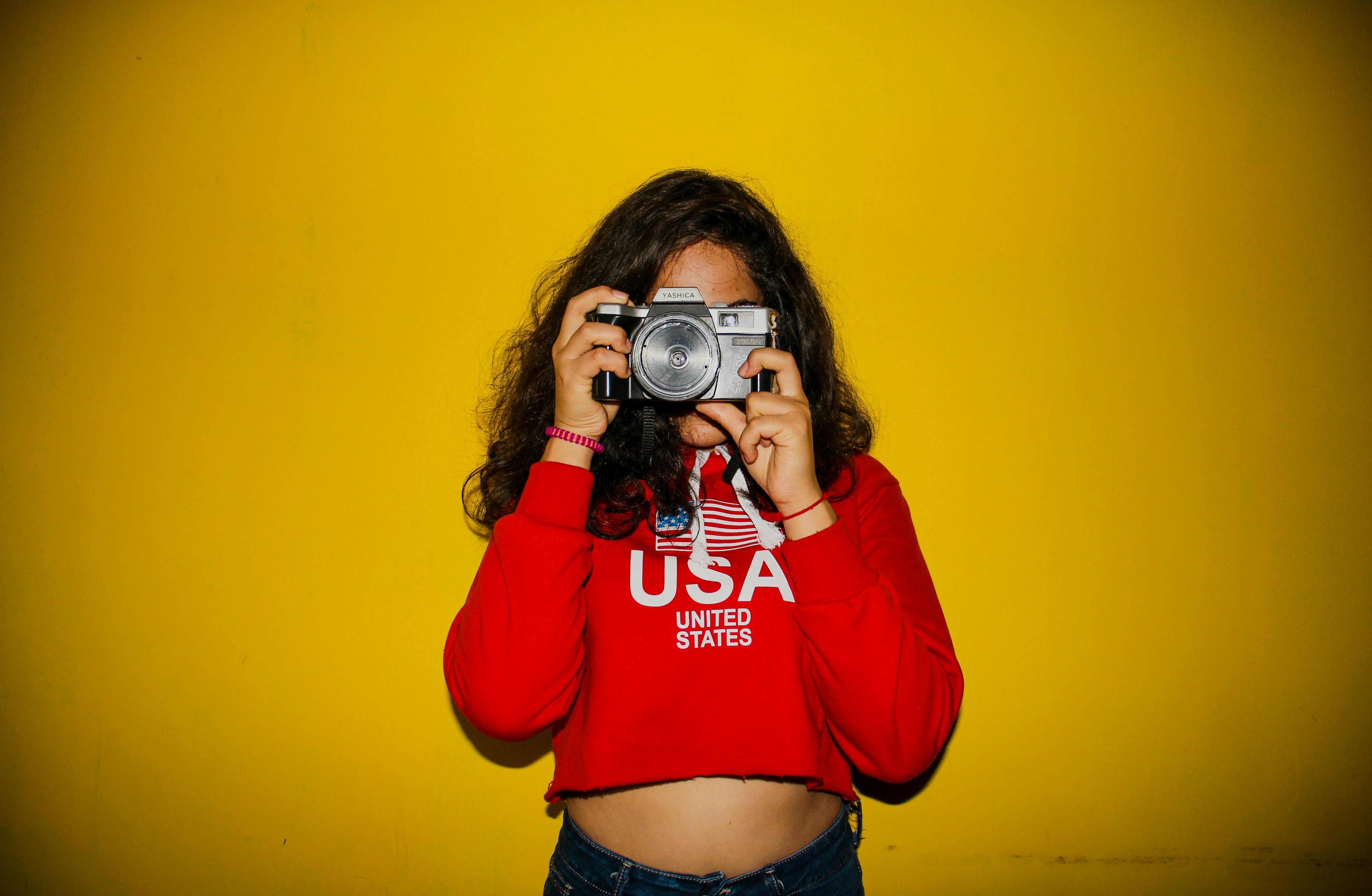 Photo of a women wearing a red crop top holding camera taking a picture ...