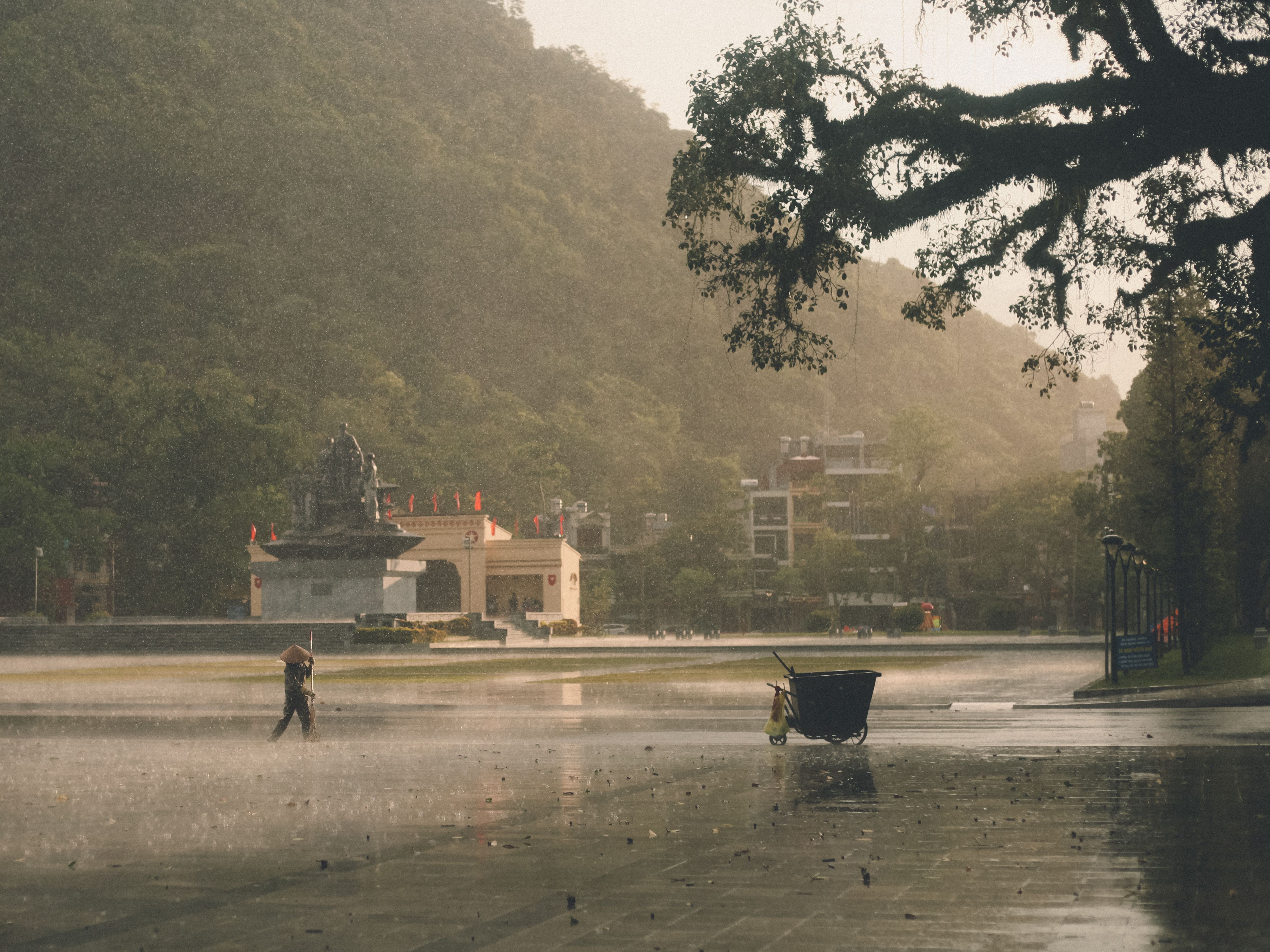 Person Cleaning Square near Temple in Downpour · Free Stock Photo