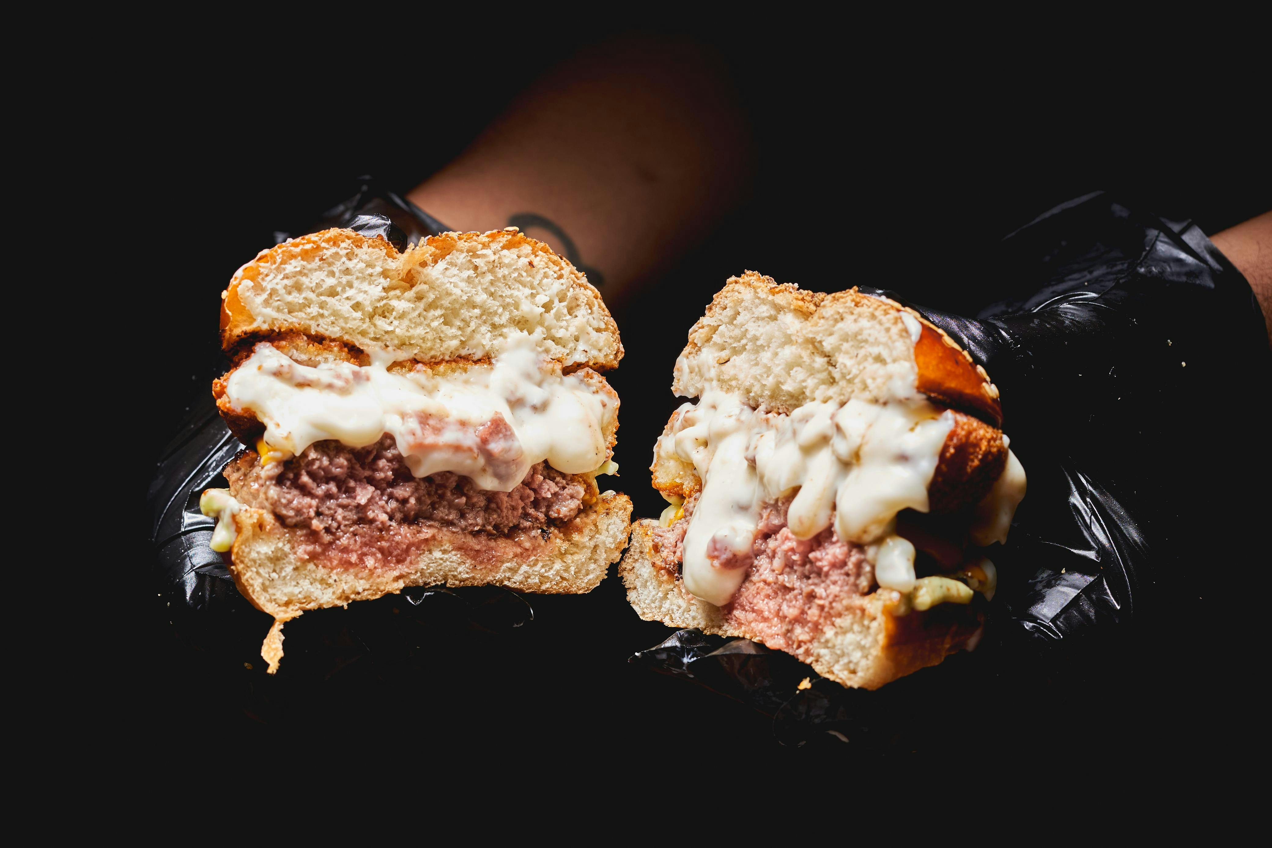 Person Holding Juicy Burger Cut in Half · Free Stock Photo