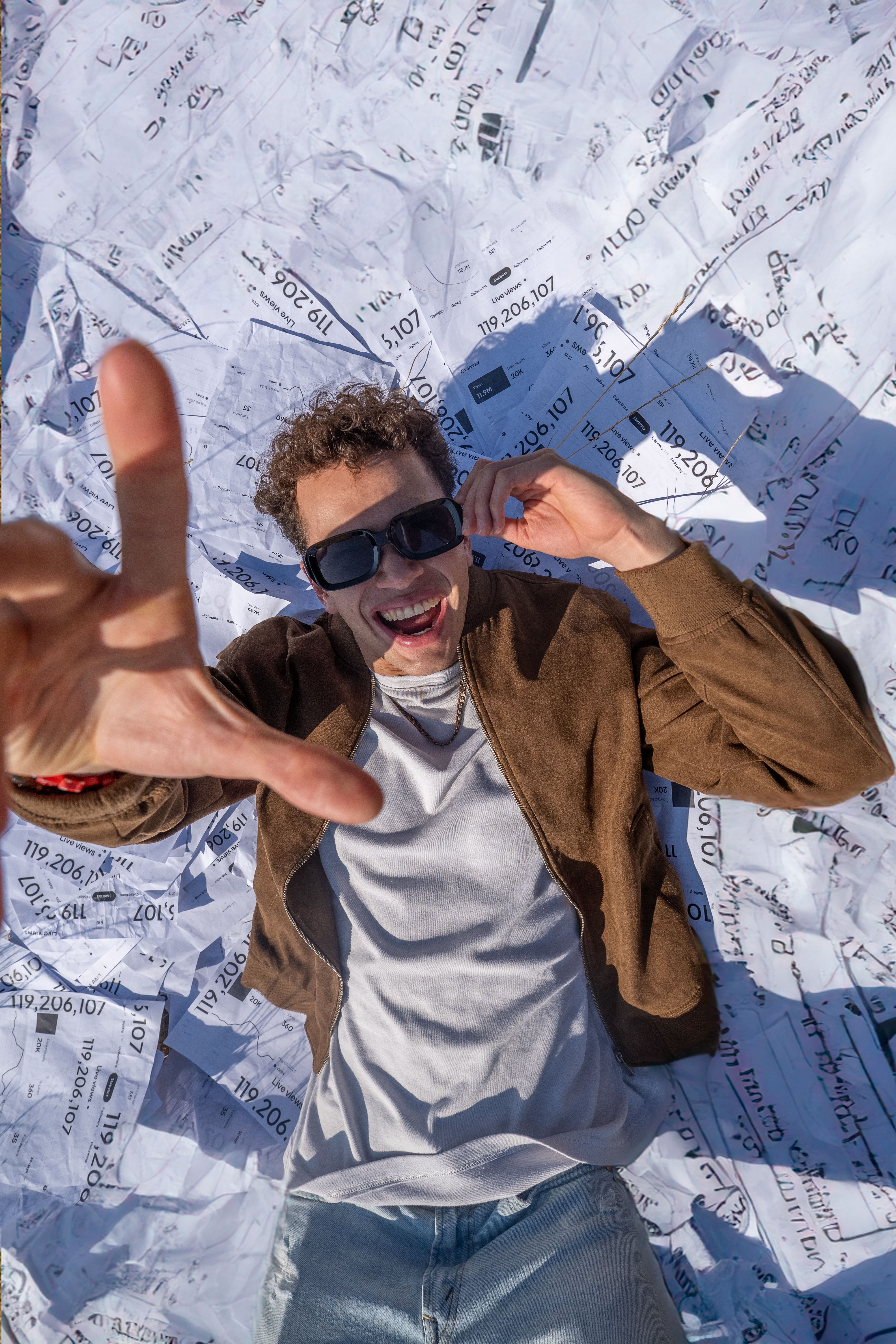 Man Lying on Pile of Documents Reaching his Hand out · Free Stock Photo