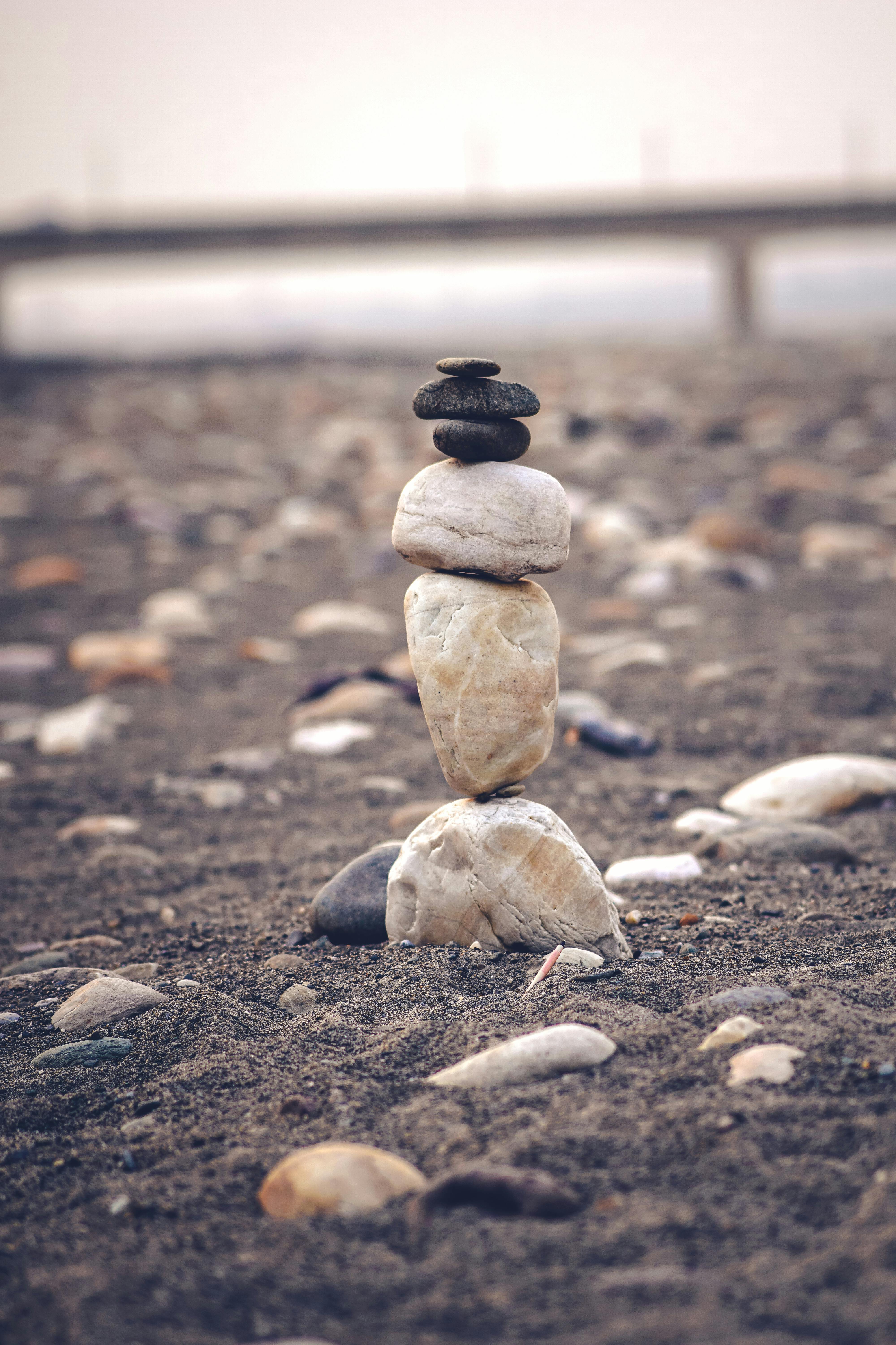 A stack of rocks on the beach with a bridge in the background · Free ...