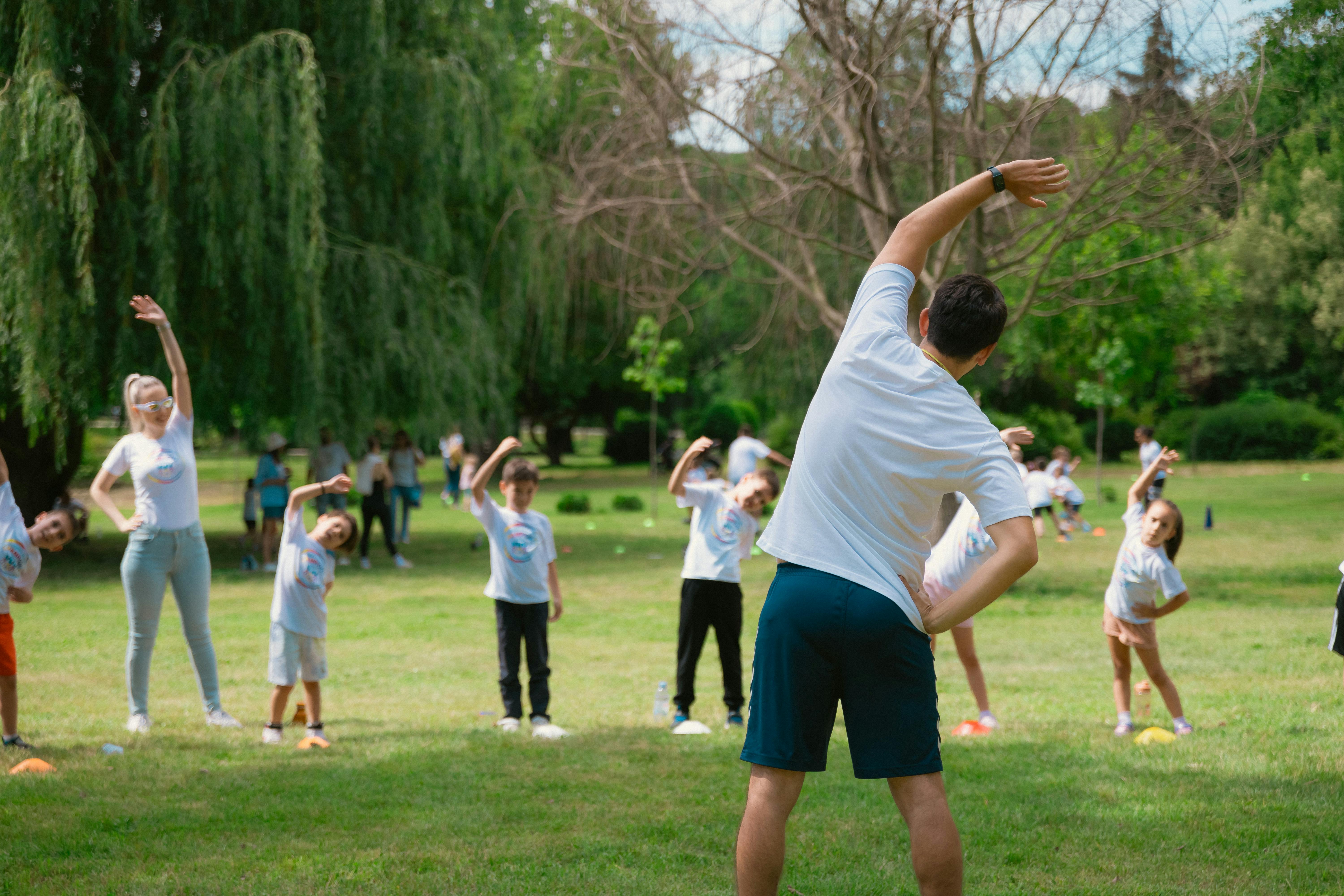 Schoolchildren Stretching on Grass during an Outdoor Physical Education ...