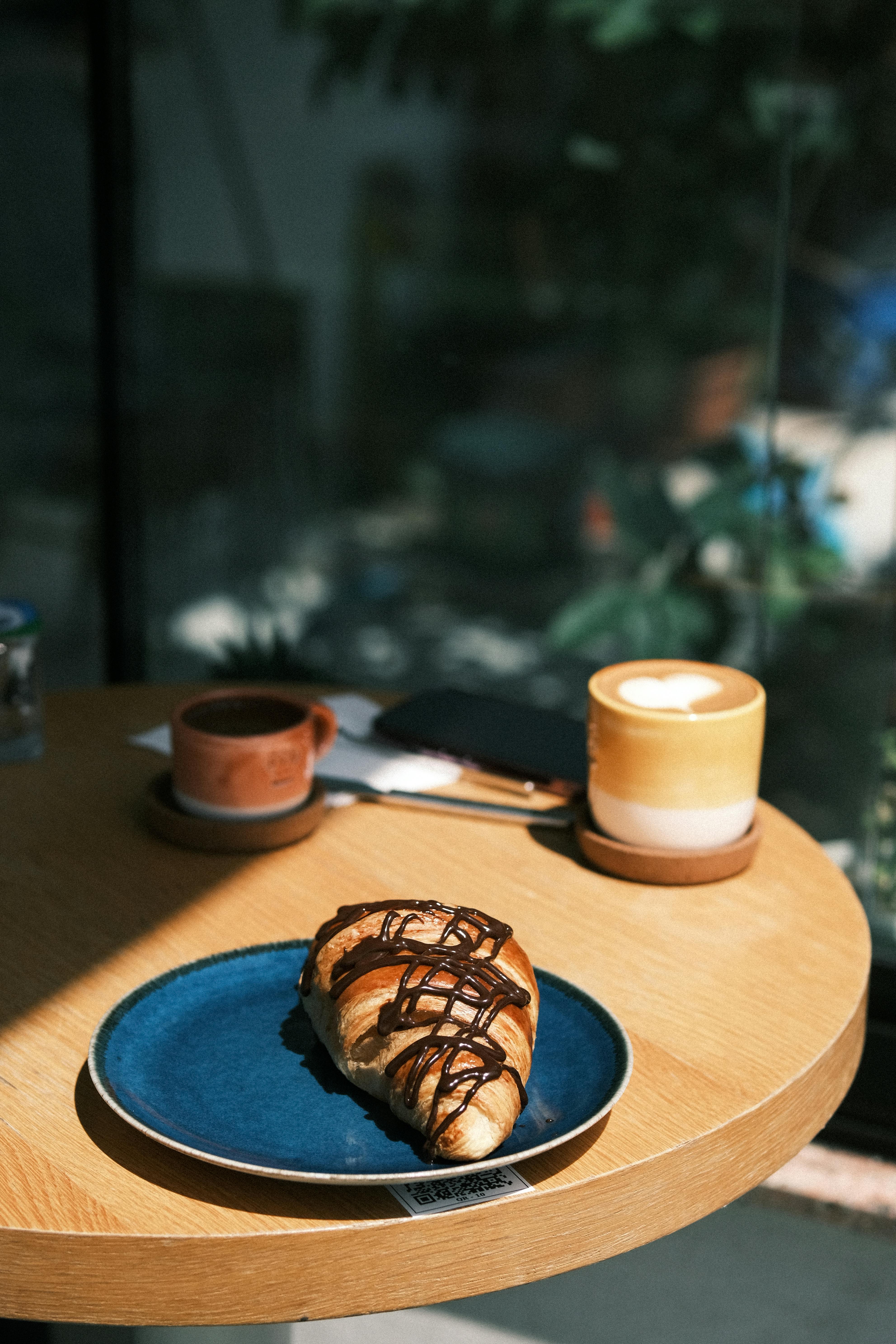 A Croissant with Chocolate and a Cup of Coffee Standing on the Table ...