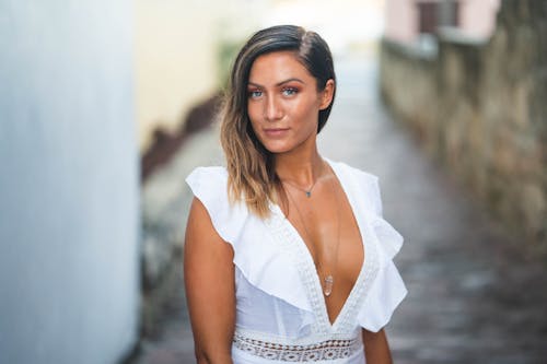 Woman In White Sleeveless Dress Standing Beside Gray Wooden Wall · Free