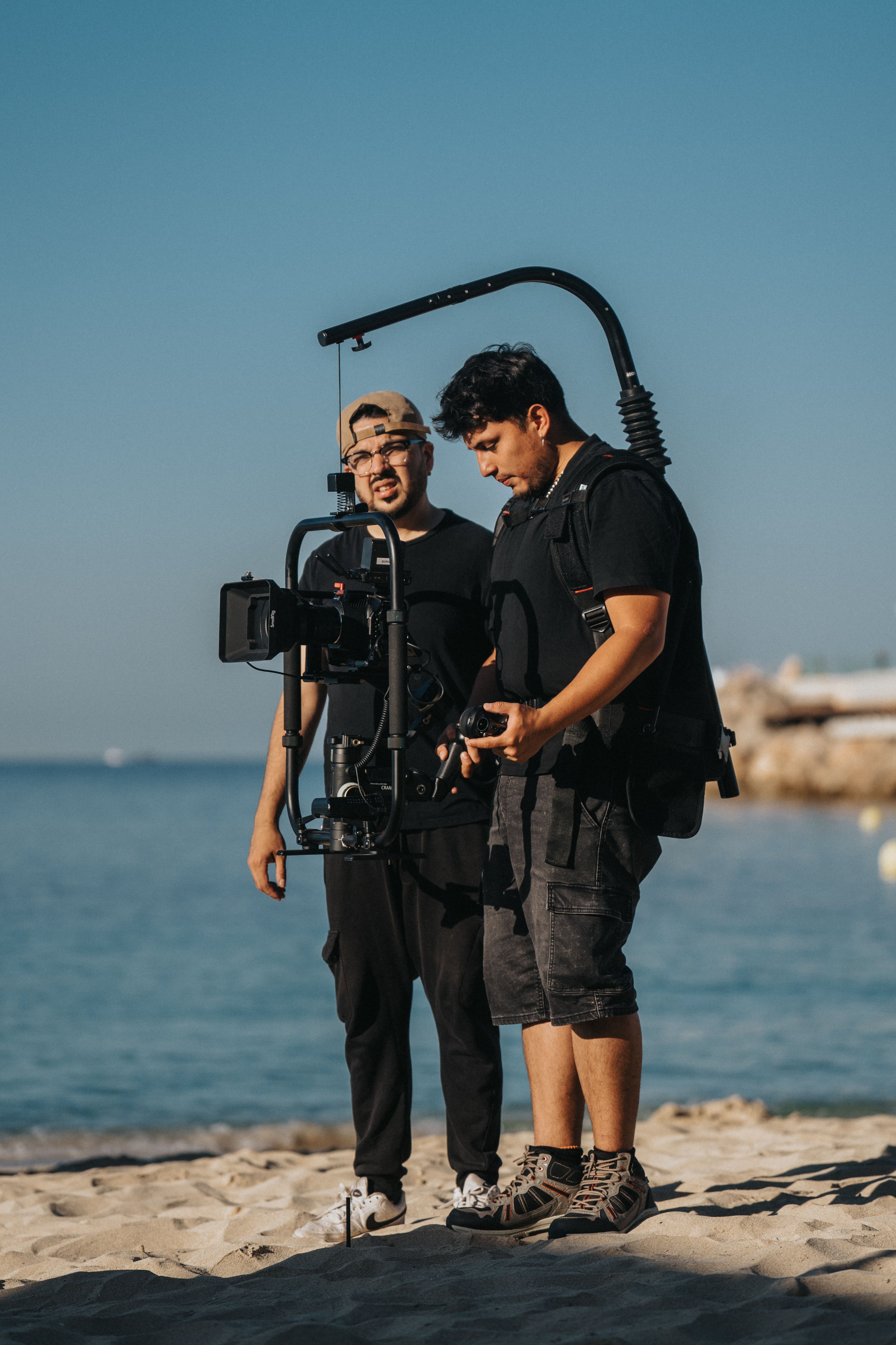 Two Men Using a Camera with a Stabilizer at the Coast · Free Stock Photo