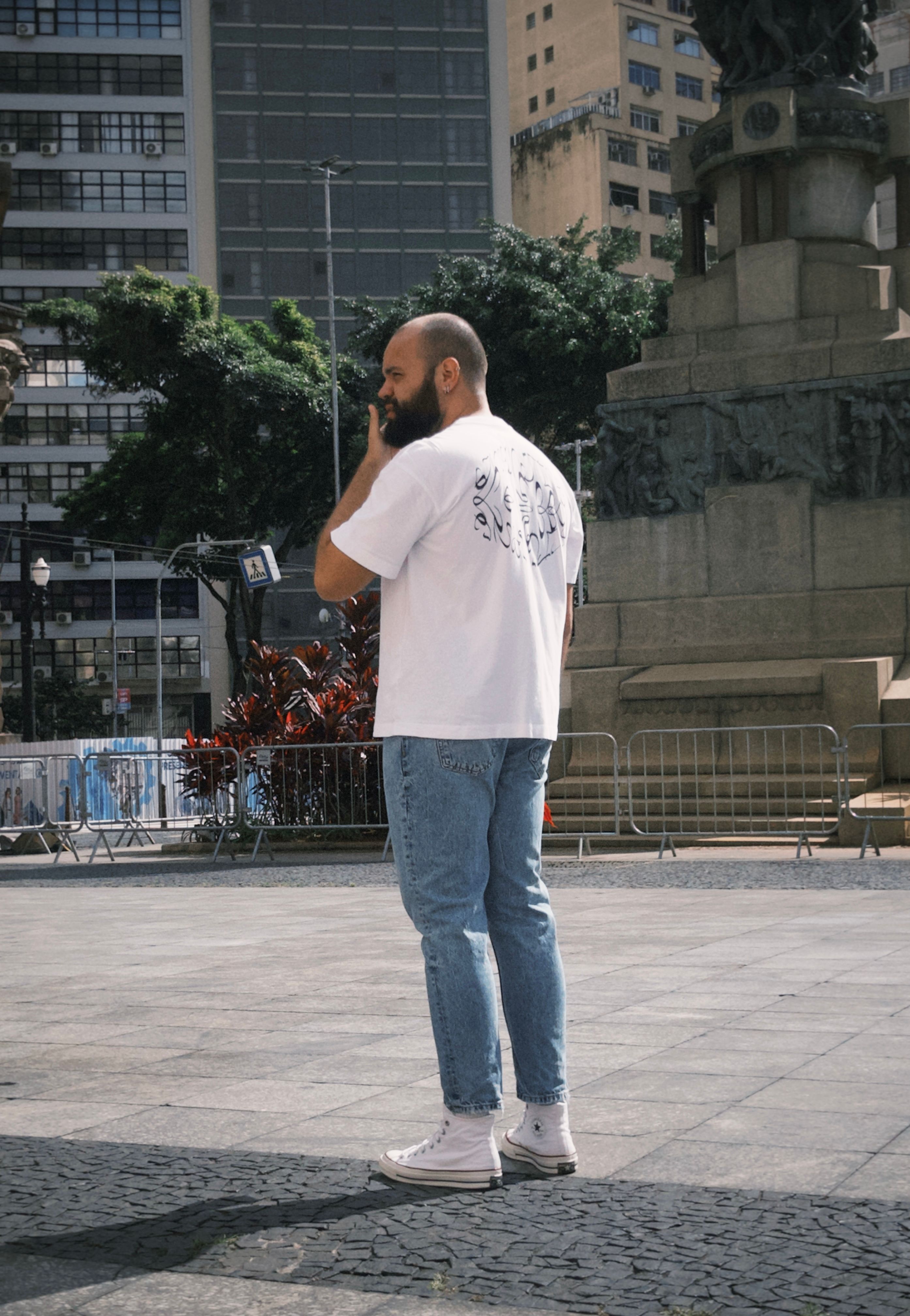 Man in Jeans Standing on Square against Monument · Free Stock Photo