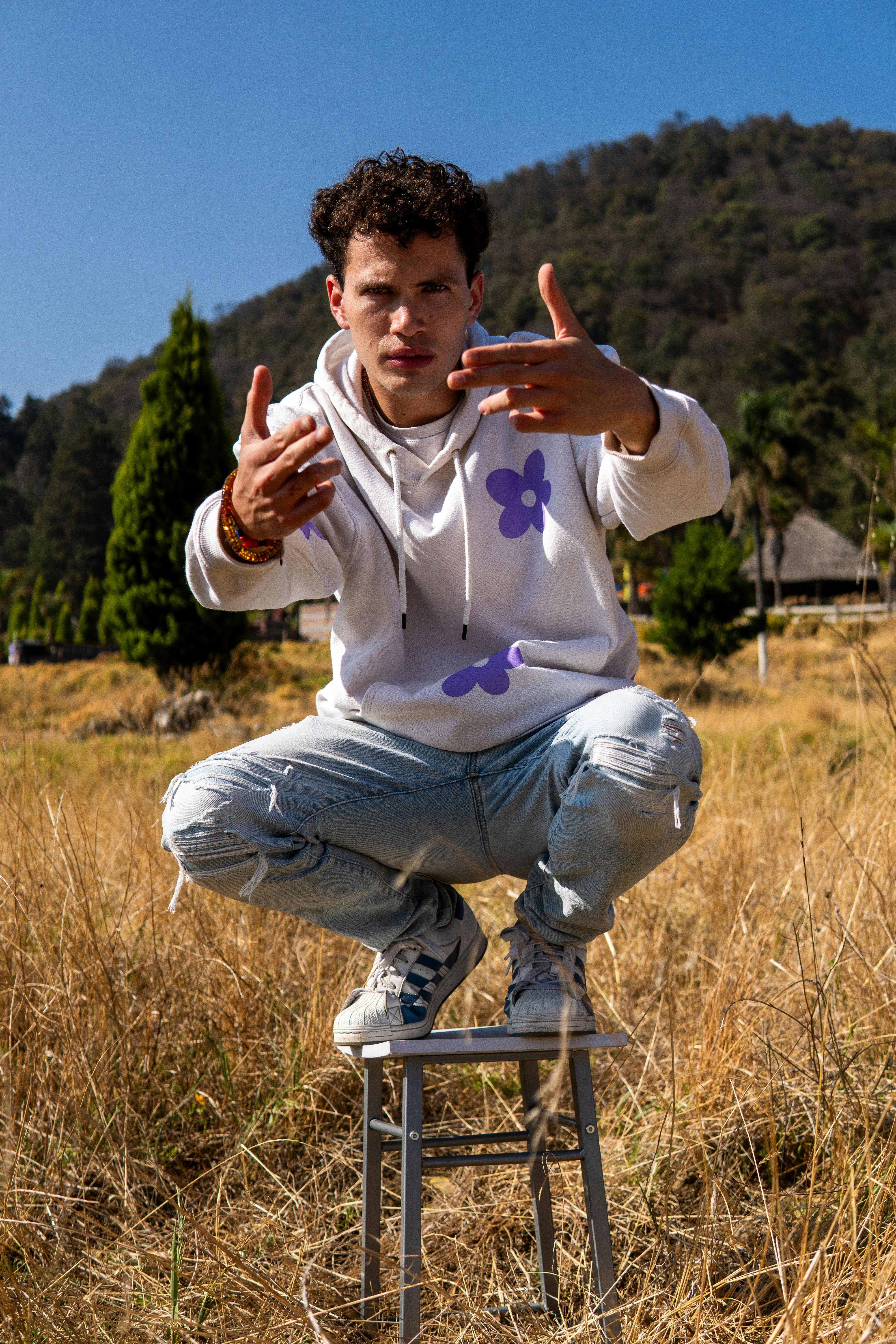 A Young Man Crouching on a Chair on the Field · Free Stock Photo