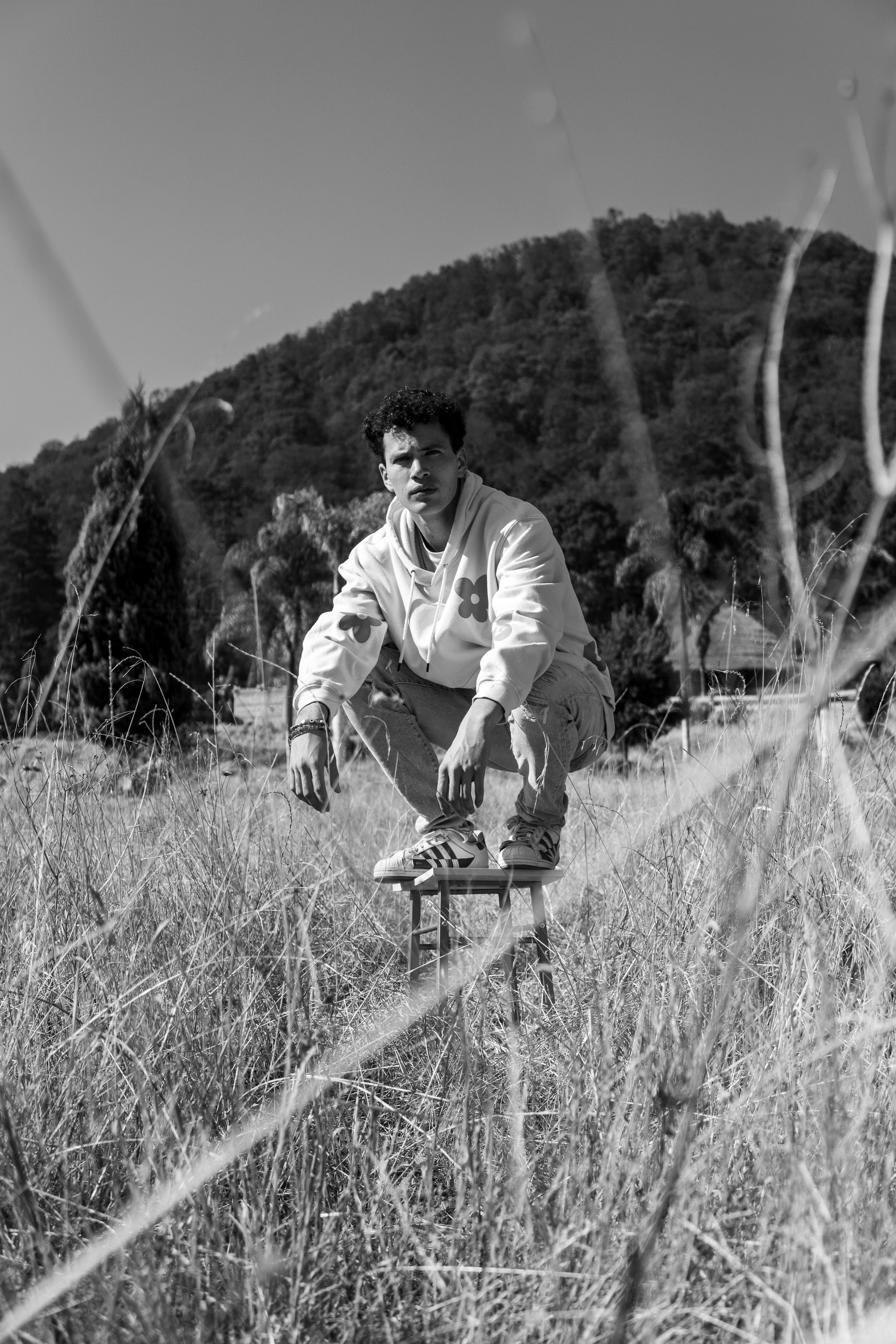 A Young Man Crouching on a Chair on the Field · Free Stock Photo