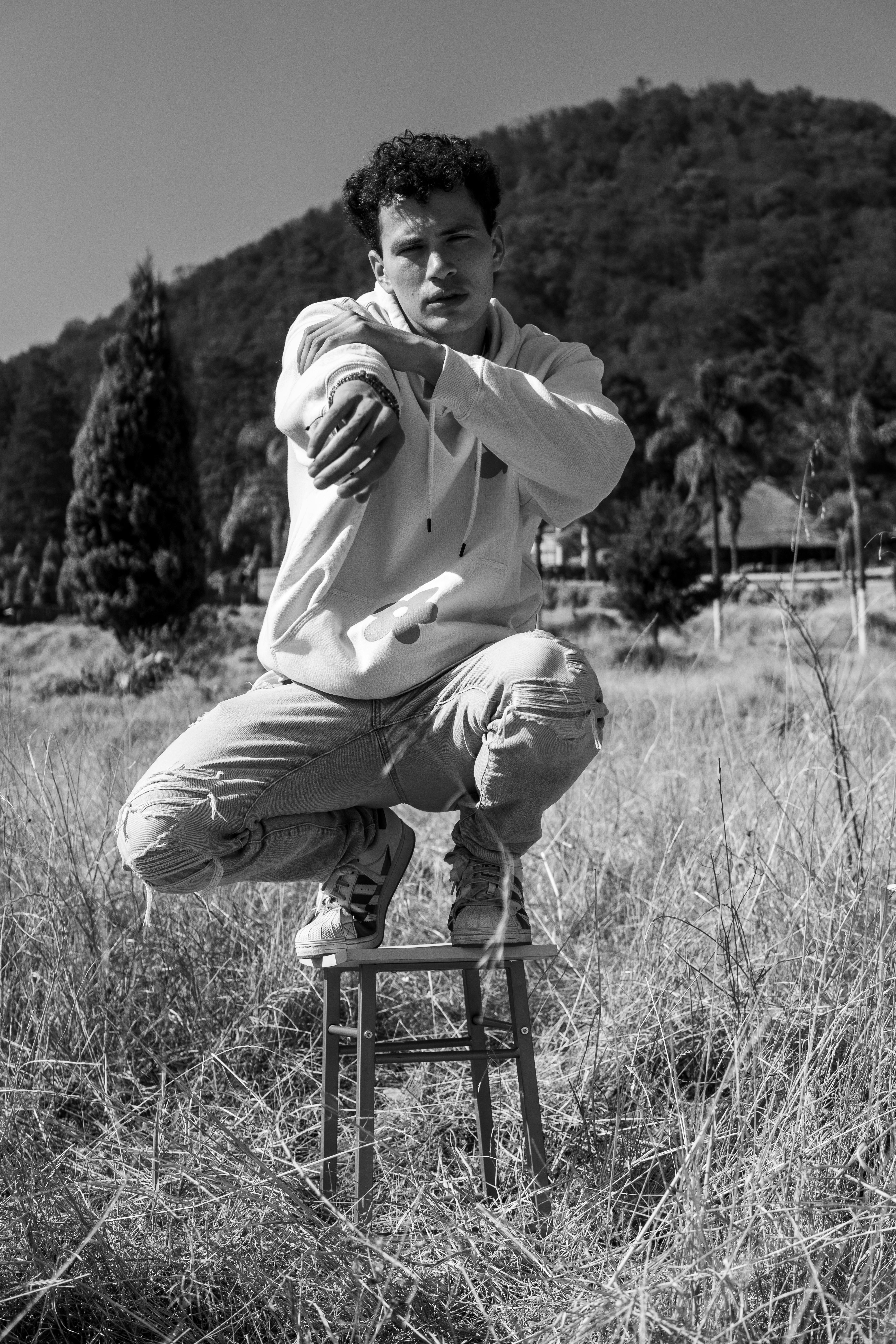 A Young Man Crouching on a Chair on the Field · Free Stock Photo