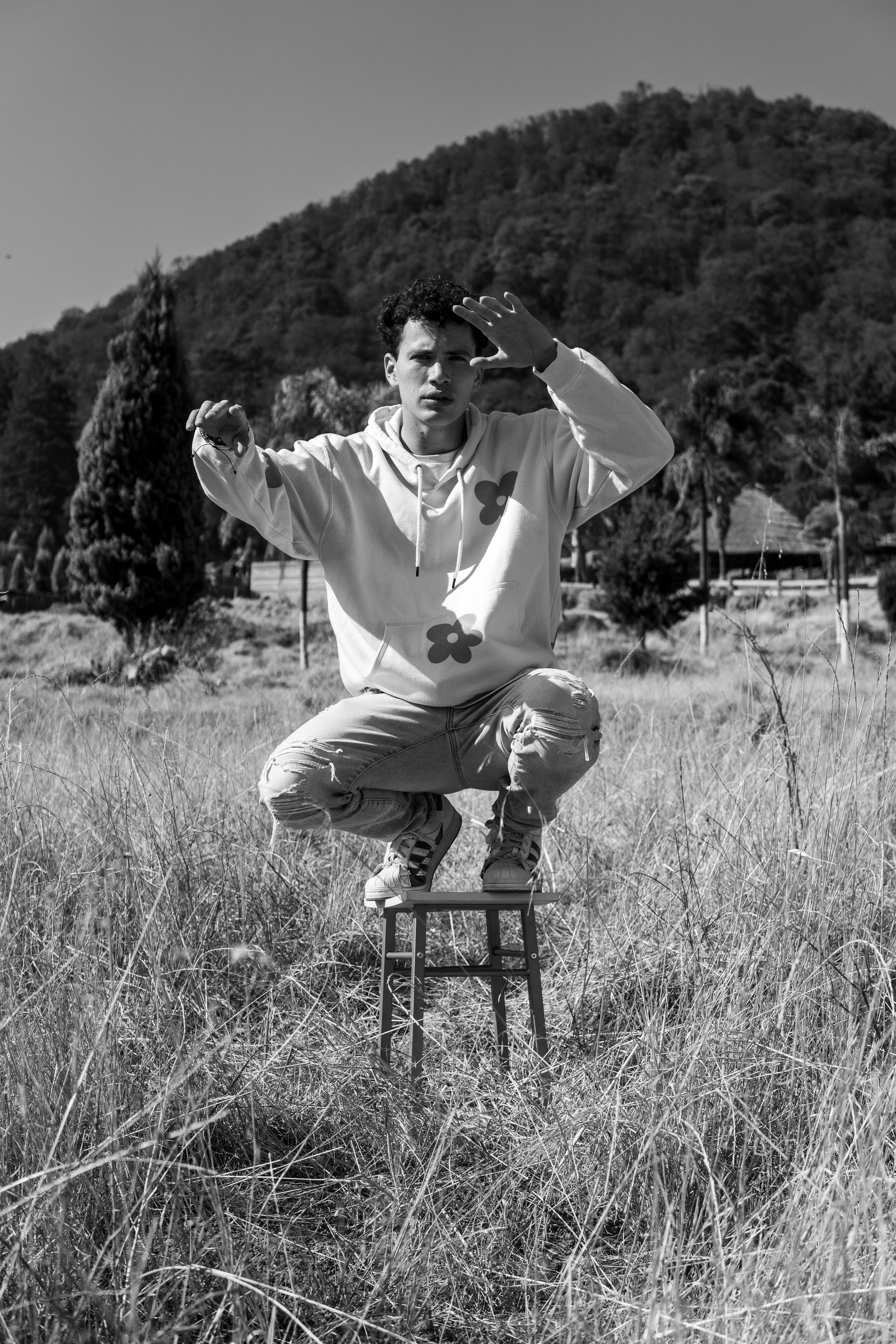 A Young Man Crouching on a Chair on the Field · Free Stock Photo