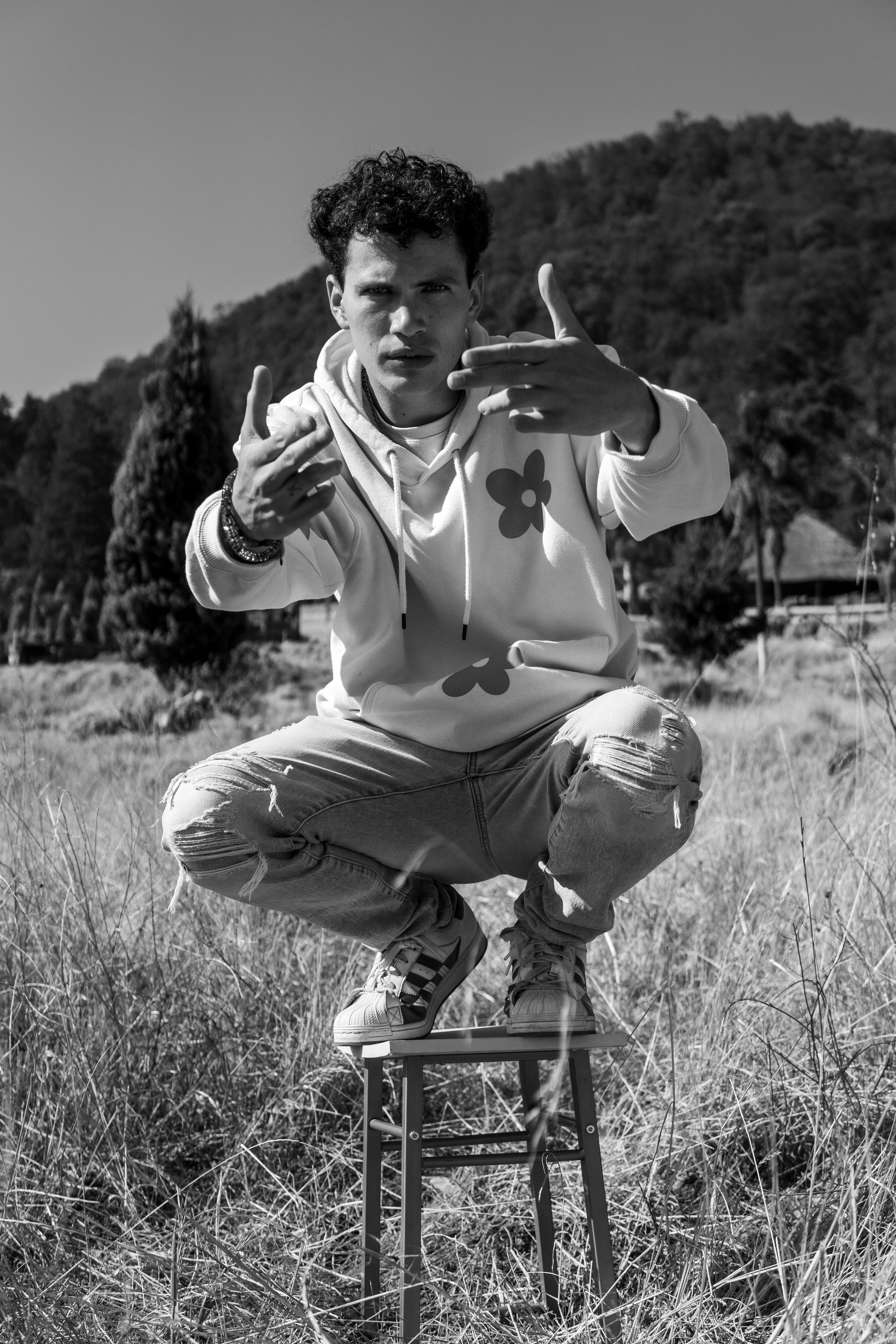 A Young Man Crouching on a Chair on the Field · Free Stock Photo
