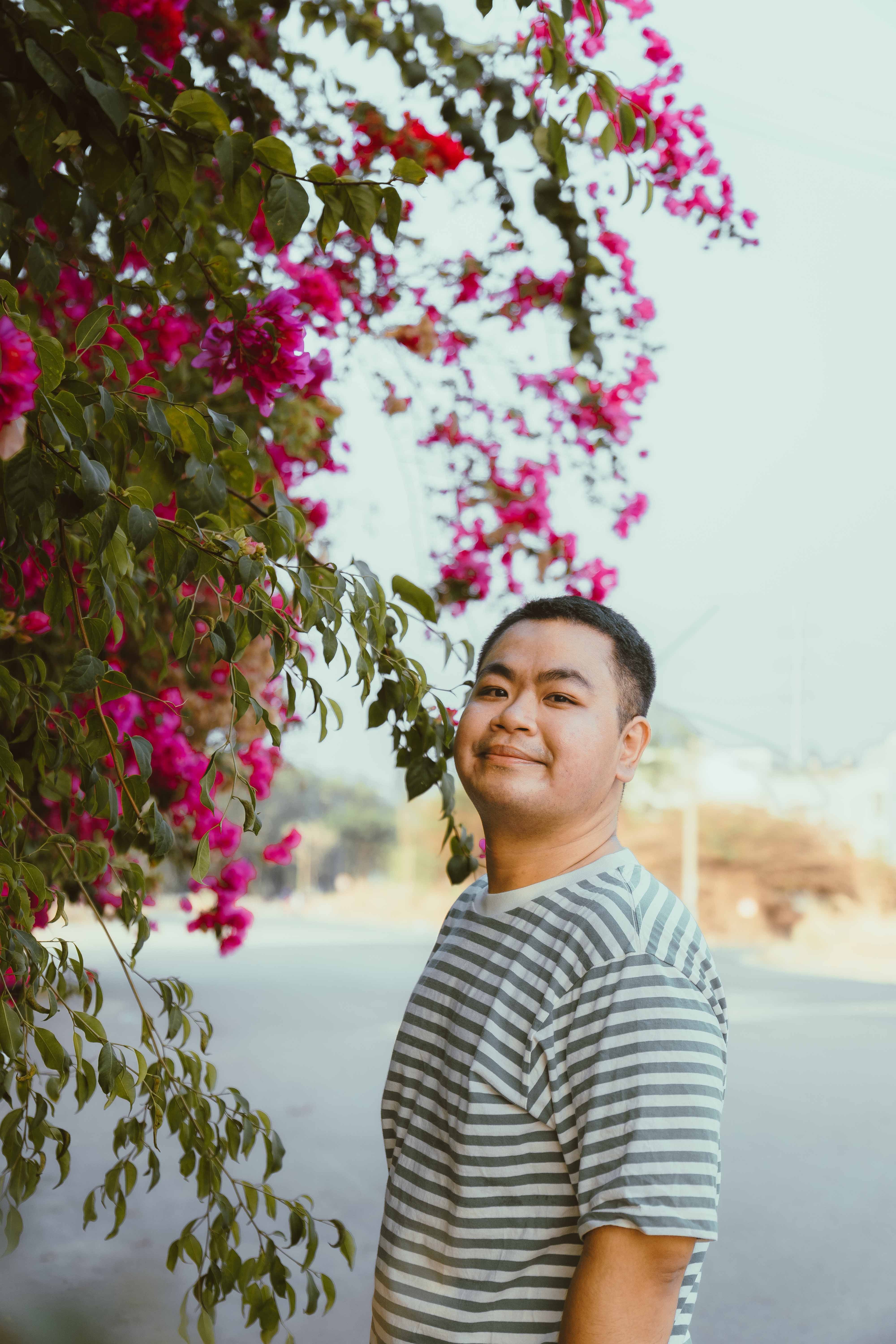 Man Smiling Posing under Tree with Pink Flowers · Free Stock Photo