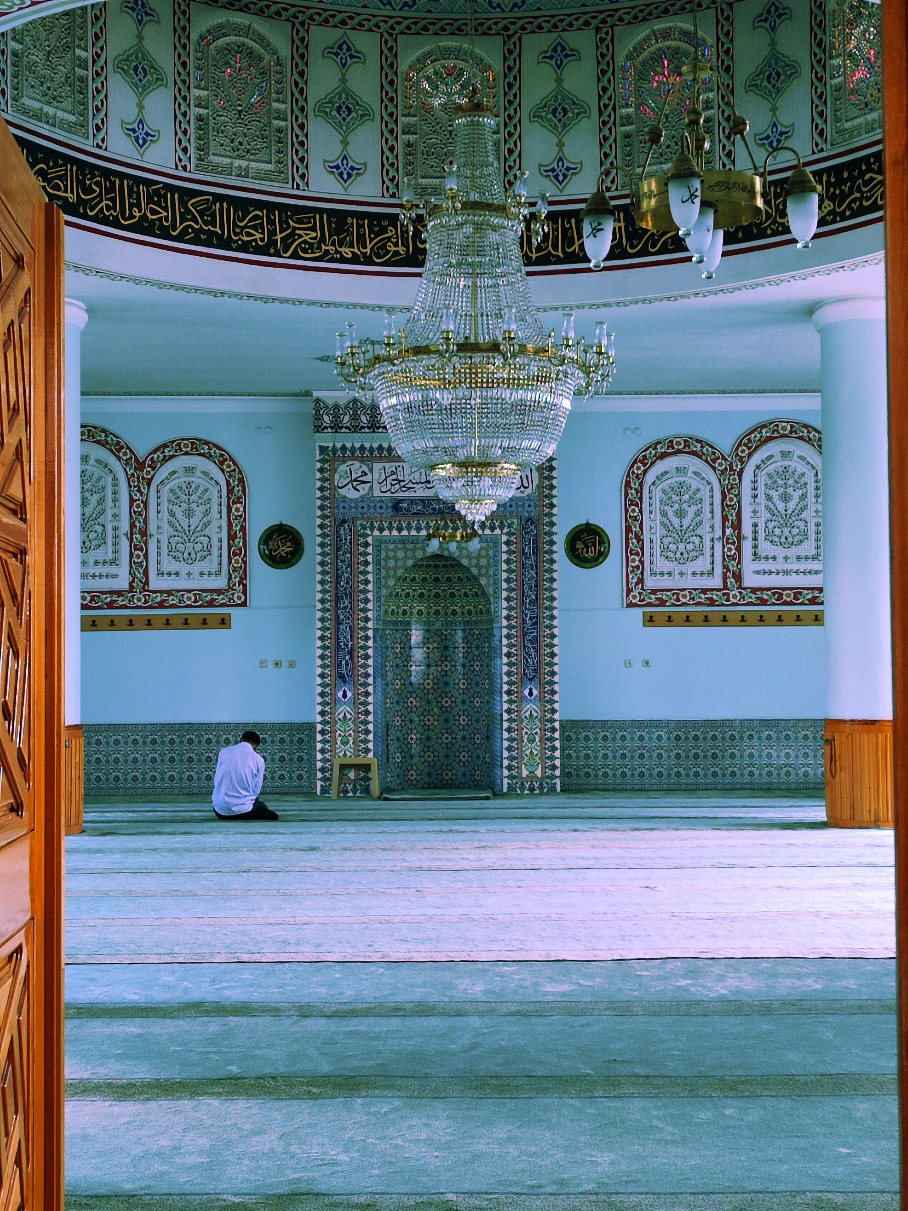 A man sitting in a mosque with a large door · Free Stock Photo