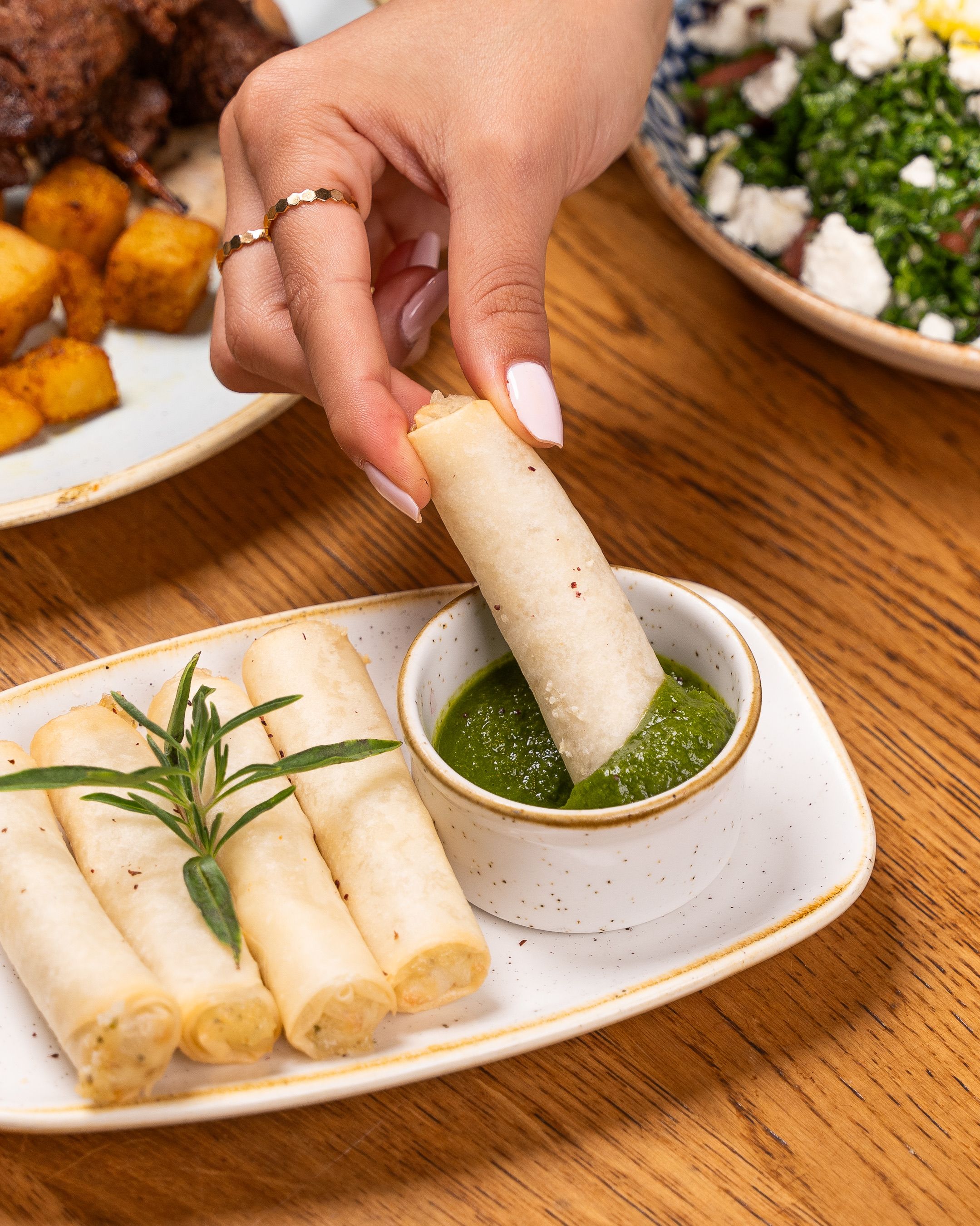 A person dipping a piece of food into a bowl of greens · Free Stock Photo