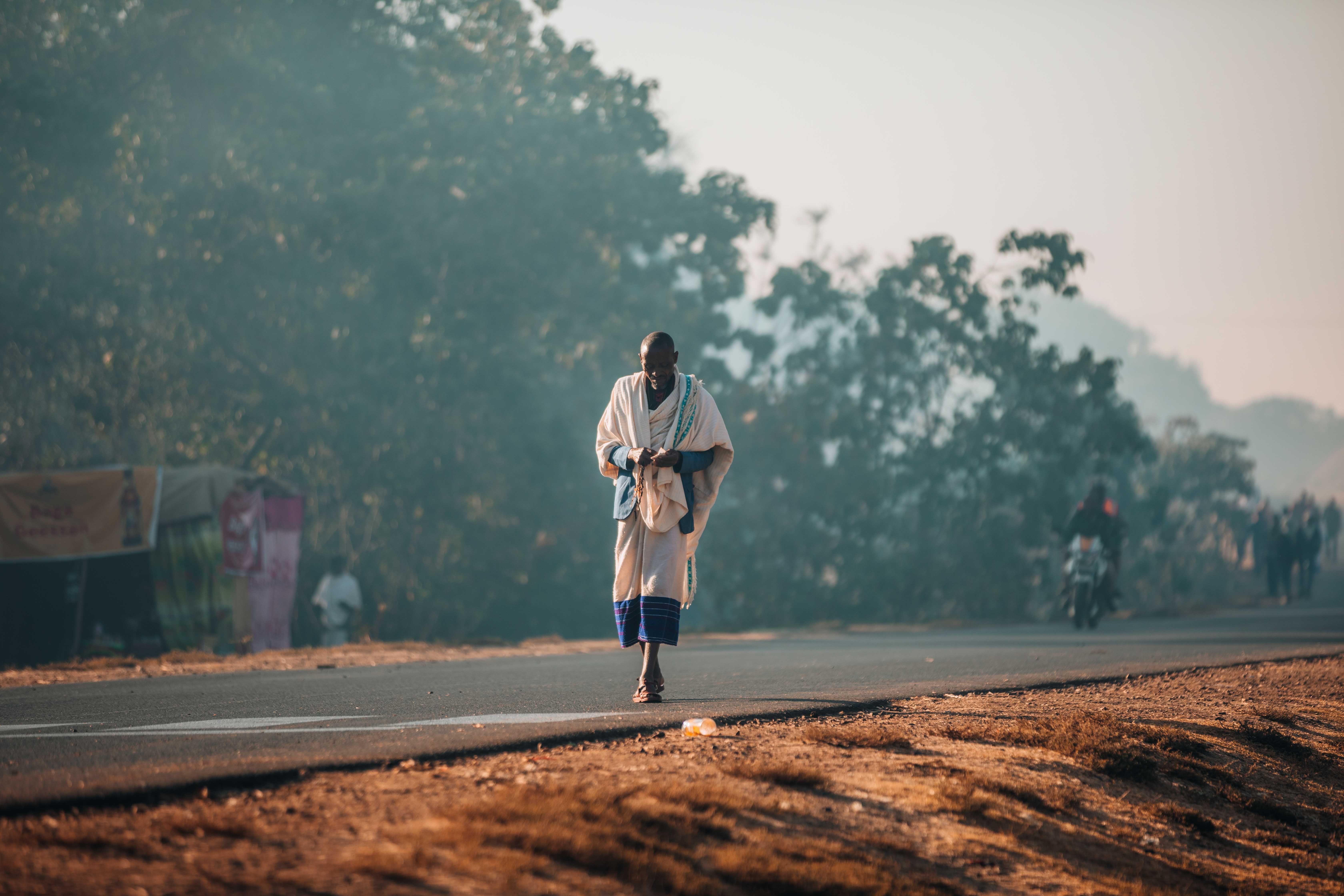 A man walking down the road with a blanket · Free Stock Photo
