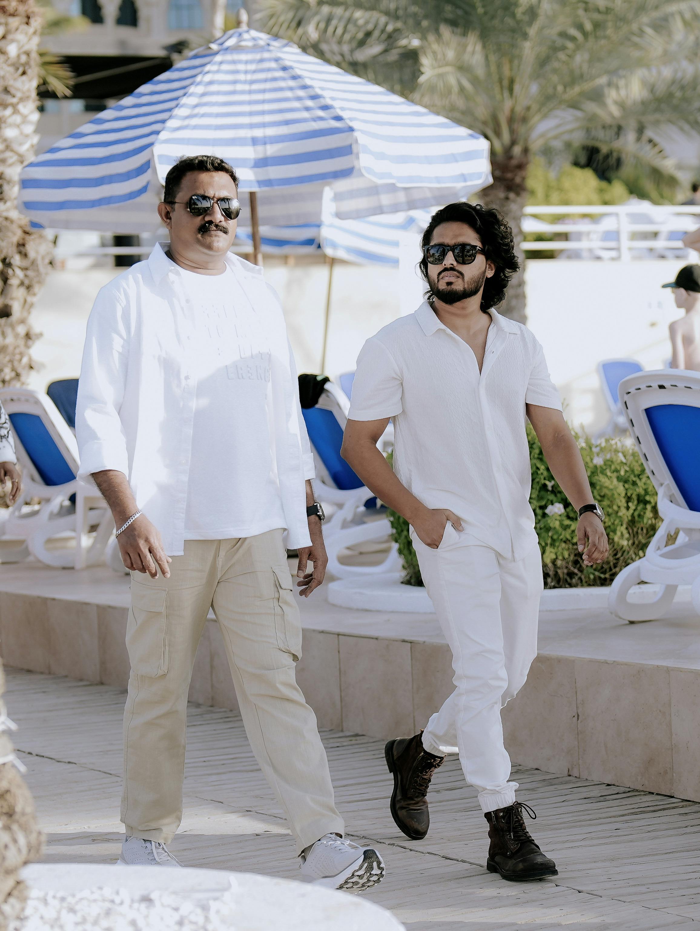 Men in Light Summer Clothing and Sunglasses Walking between Sunbeds ...