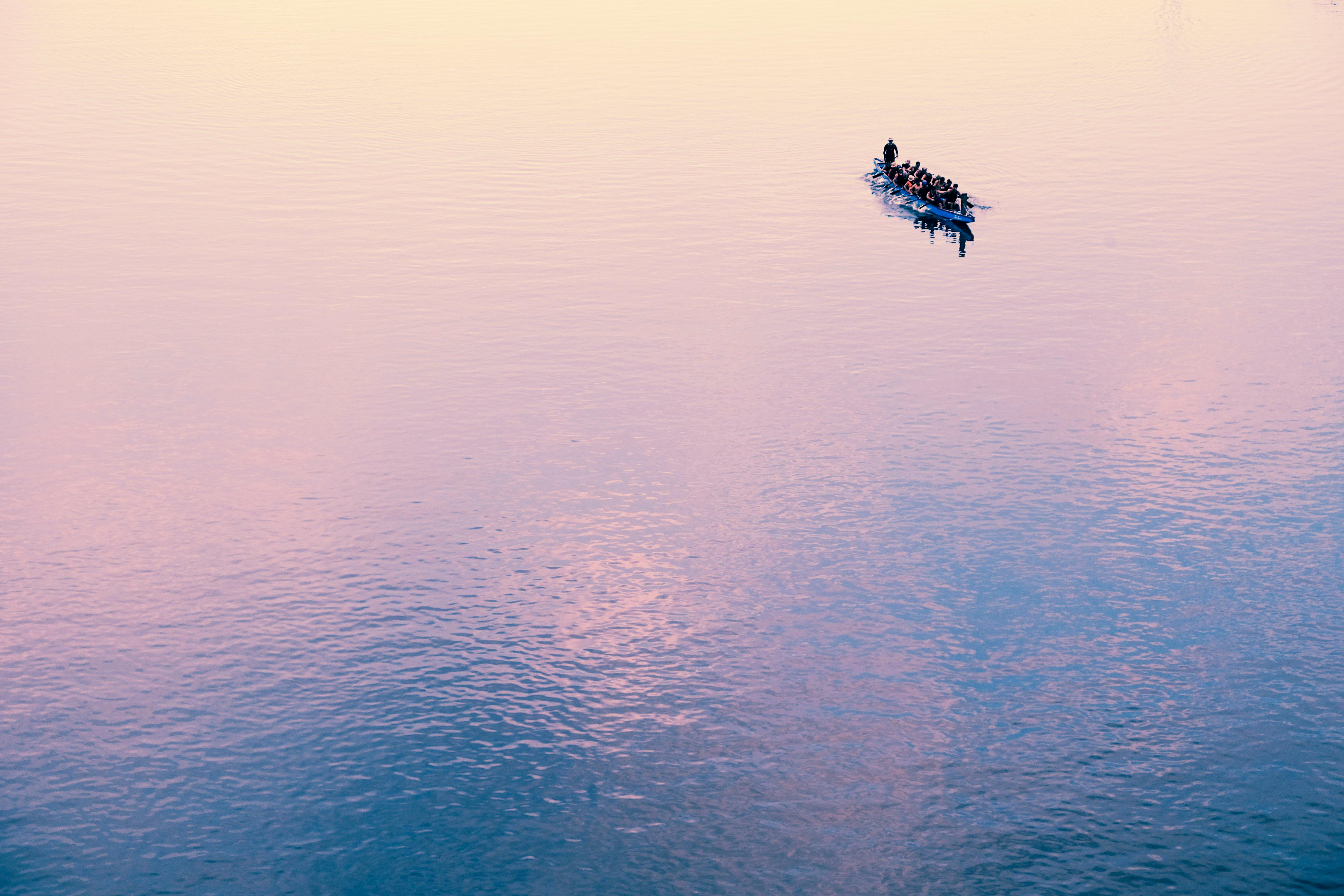Three Men Riding Boats on Body of Water · Free Stock Photo