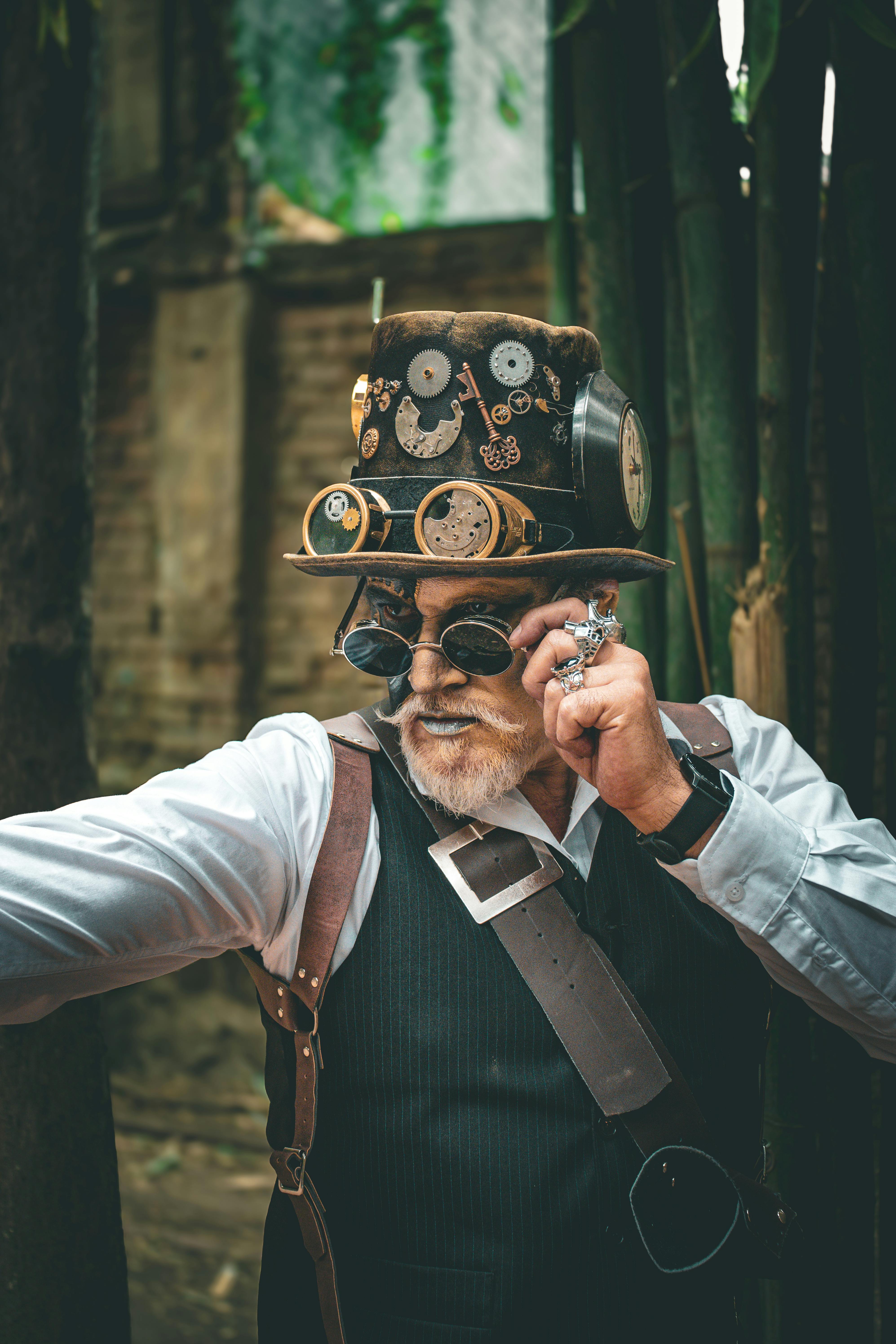A man in a top hat and goggles is holding a camera · Free Stock Photo