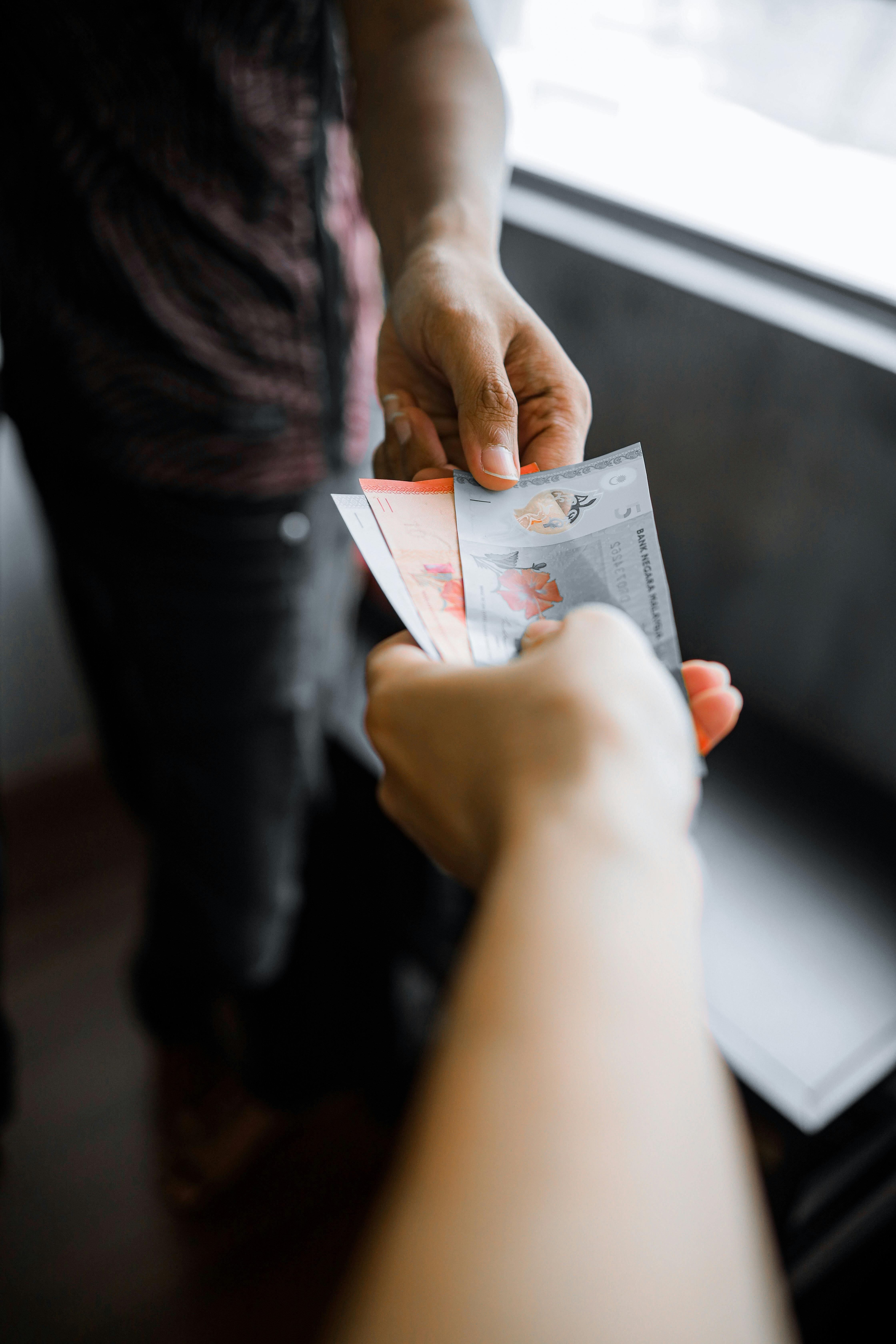 Close-up of a Person Handing Money to Another Person · Free Stock Photo