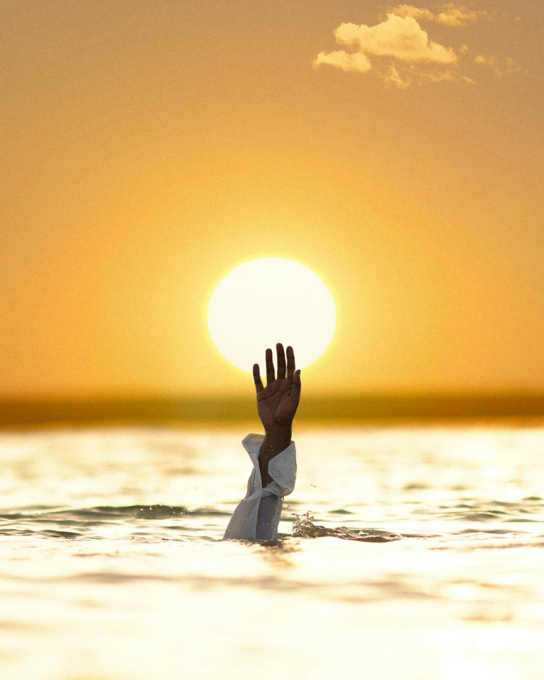 Raised Hand of Sinking Man at Sunset · Free Stock Photo