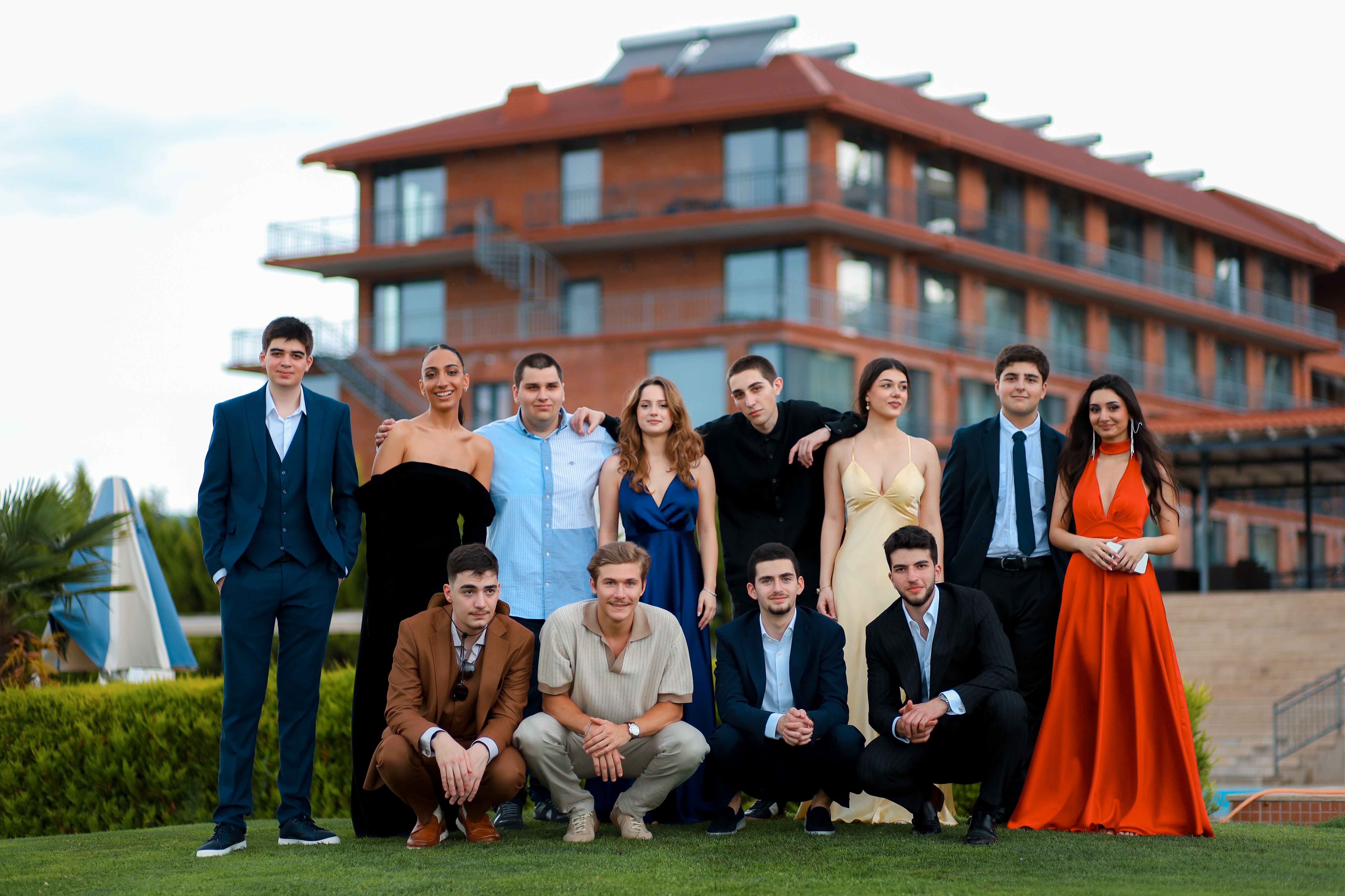 A group of people posing for a photo in front of a building · Free ...