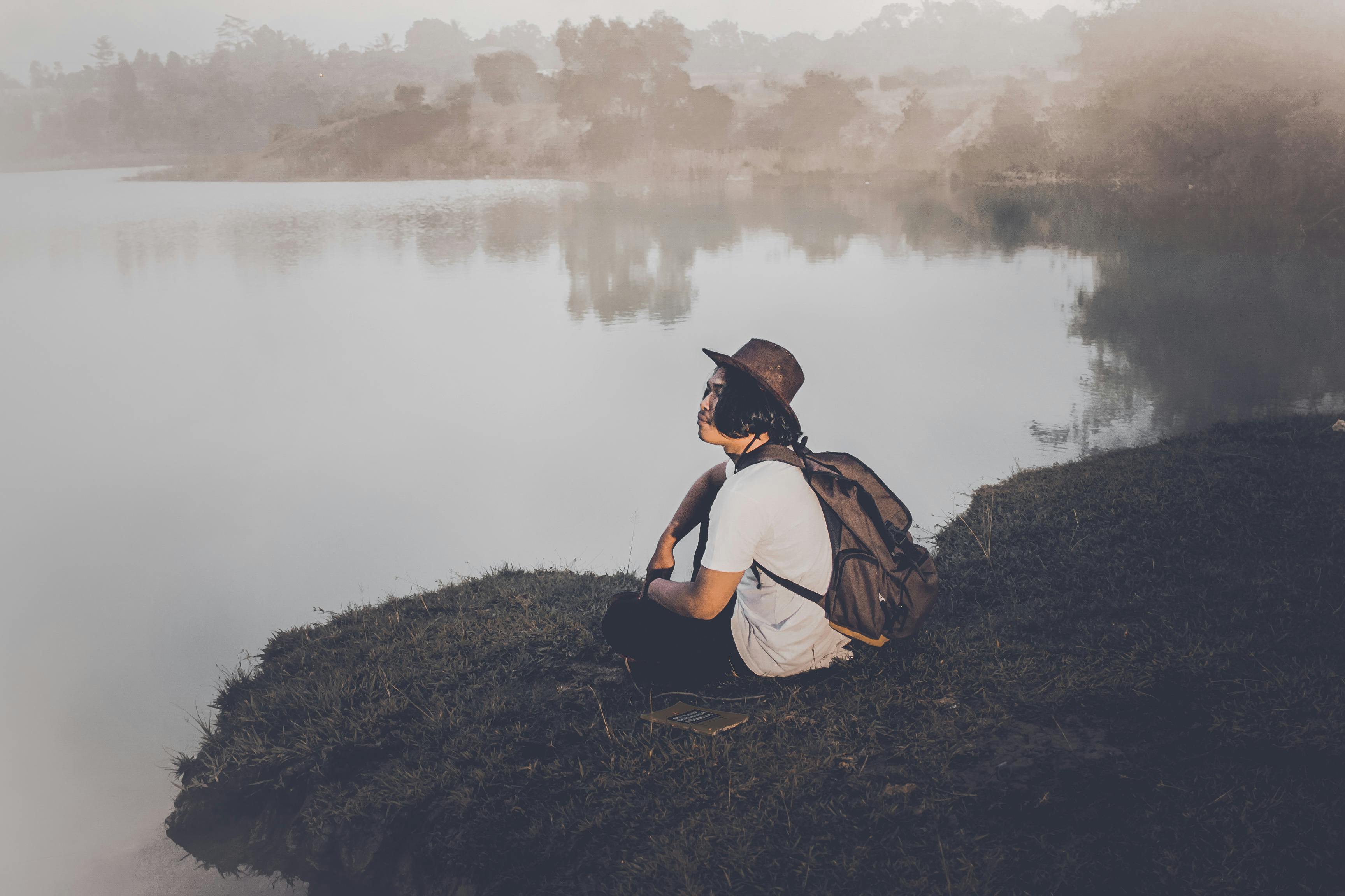 Person Sitting Near Calm Body Of Water · Free Stock Photo