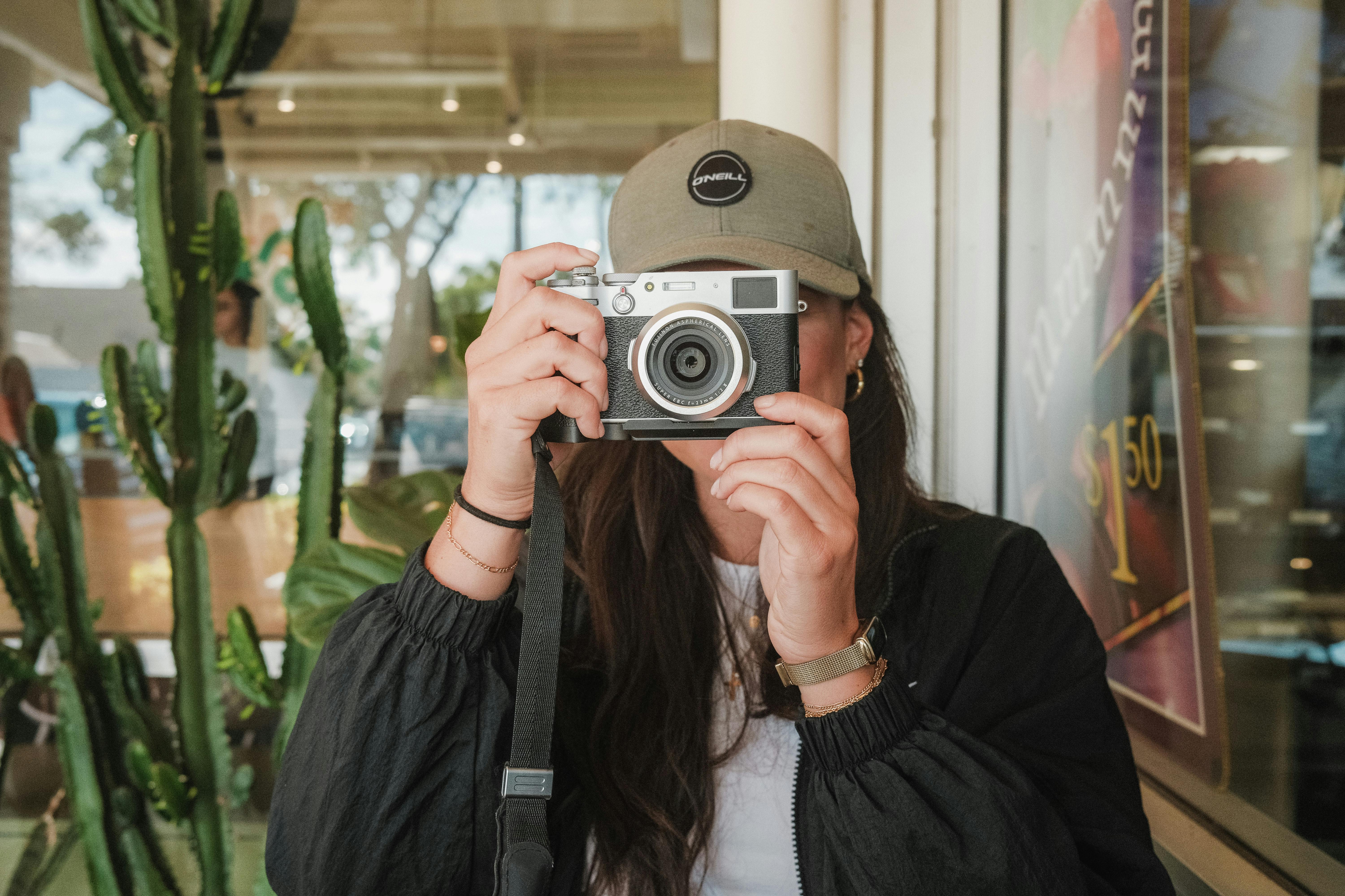 Photographer in a Cafe with a Fujifilm X100V Camera · Free Stock Photo