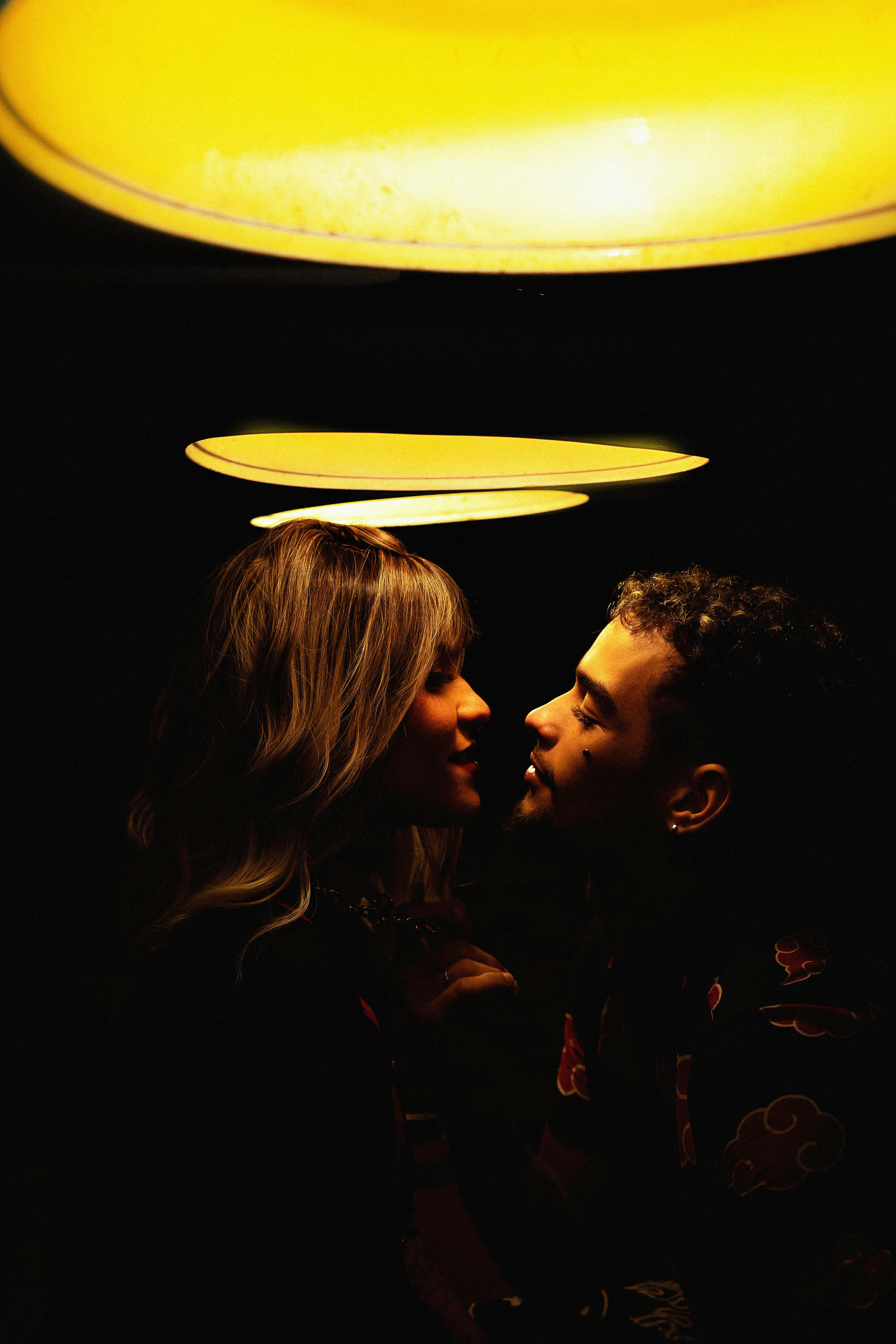A couple kissing in front of yellow lights · Free Stock Photo