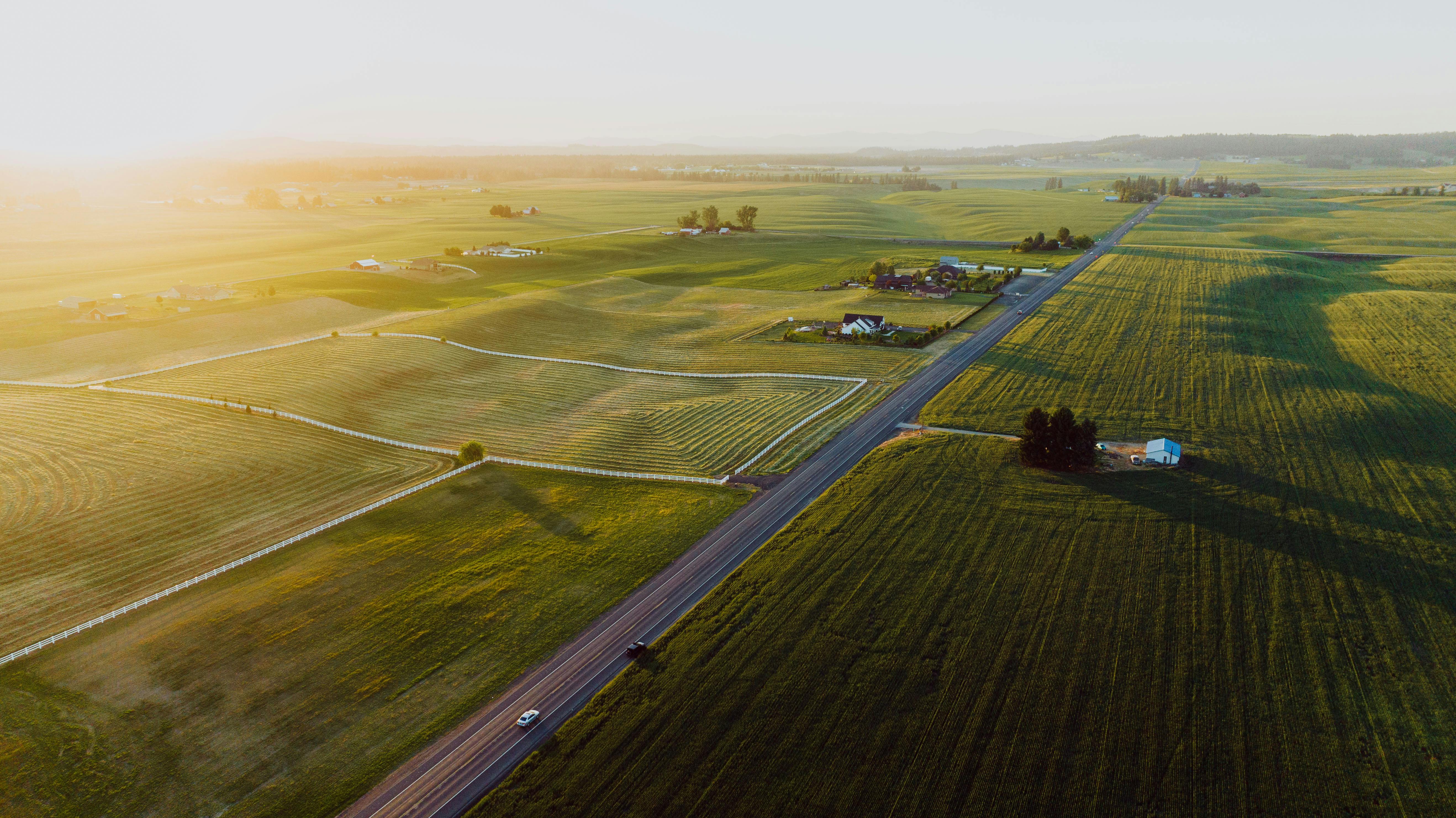Aerial View of a Country Road Stretching past Vast Green Fields · Free ...