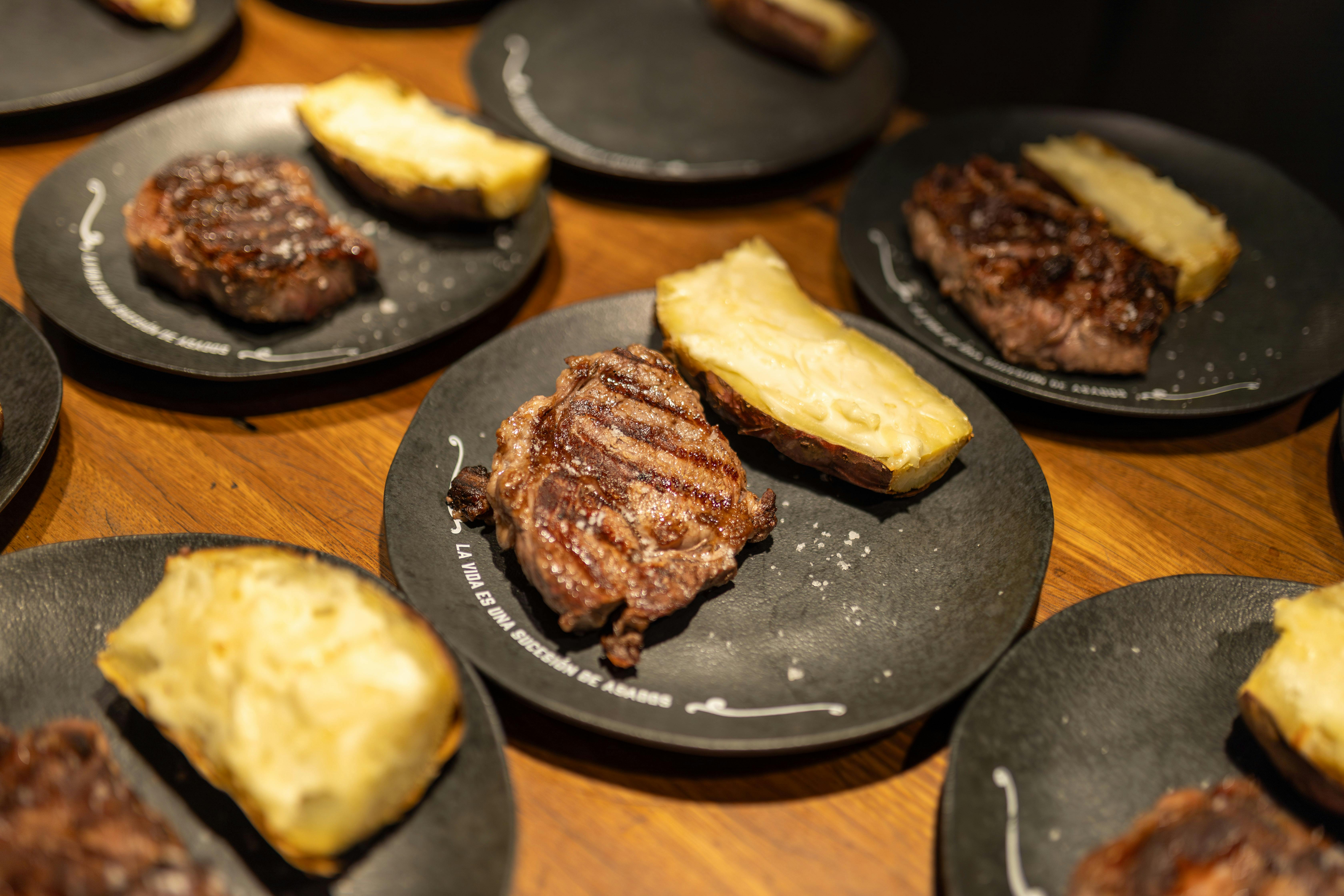 Servings of Steak on Black Plates Standing on the Table · Free Stock Photo