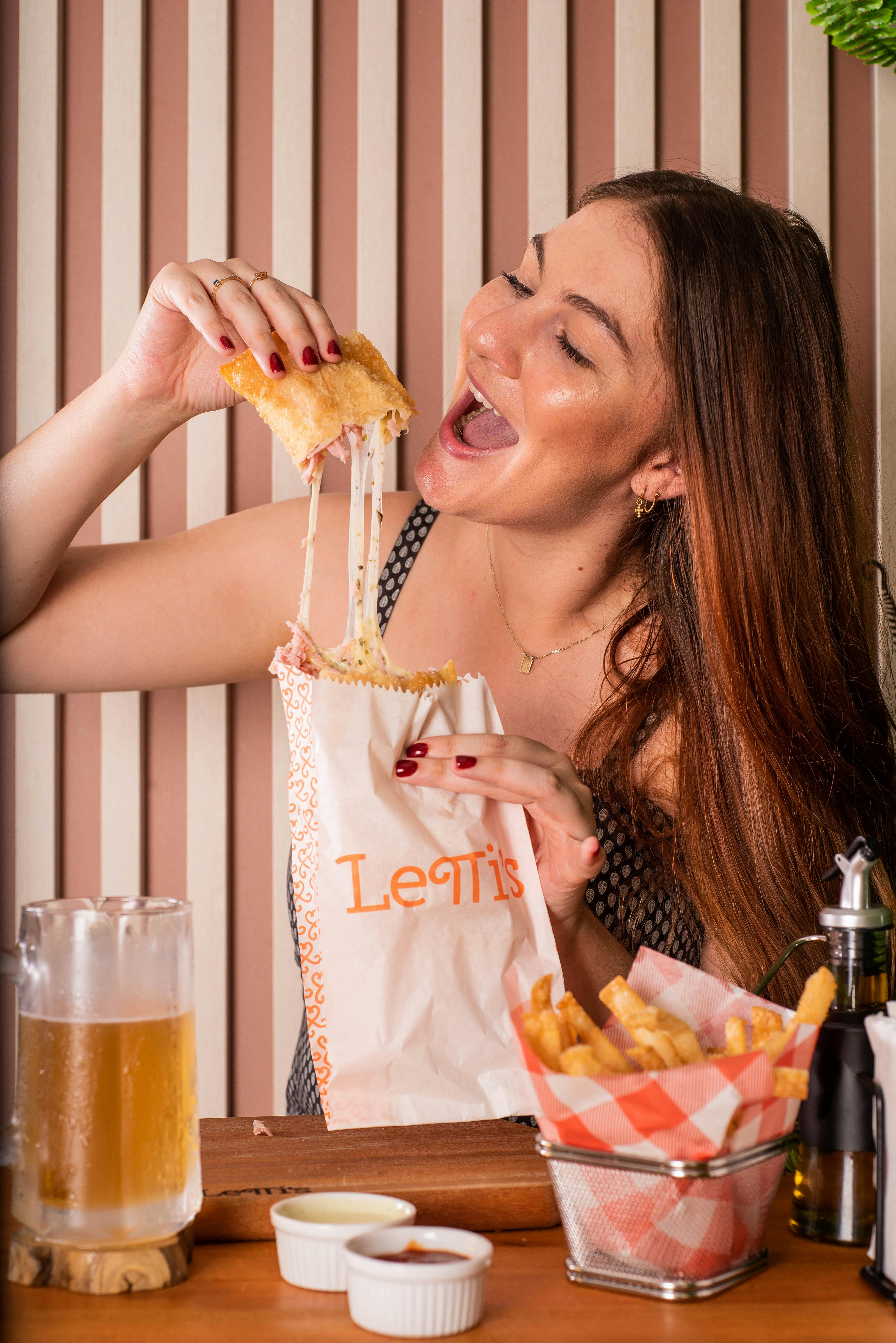 Brunette Woman Eating Cheesy Pouch with Fries in Restaurant · Free ...