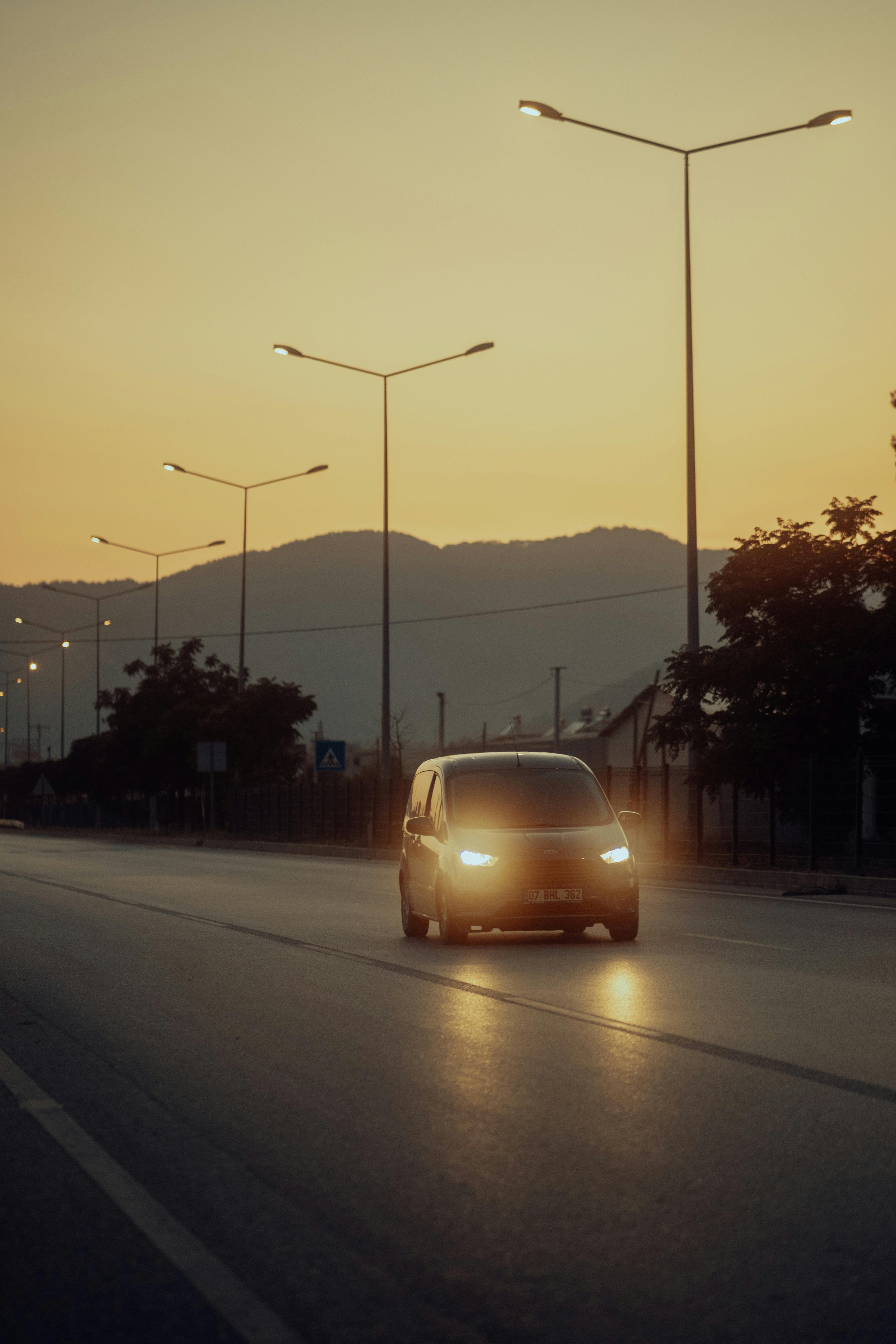 A car driving down a road at sunset · Free Stock Photo
