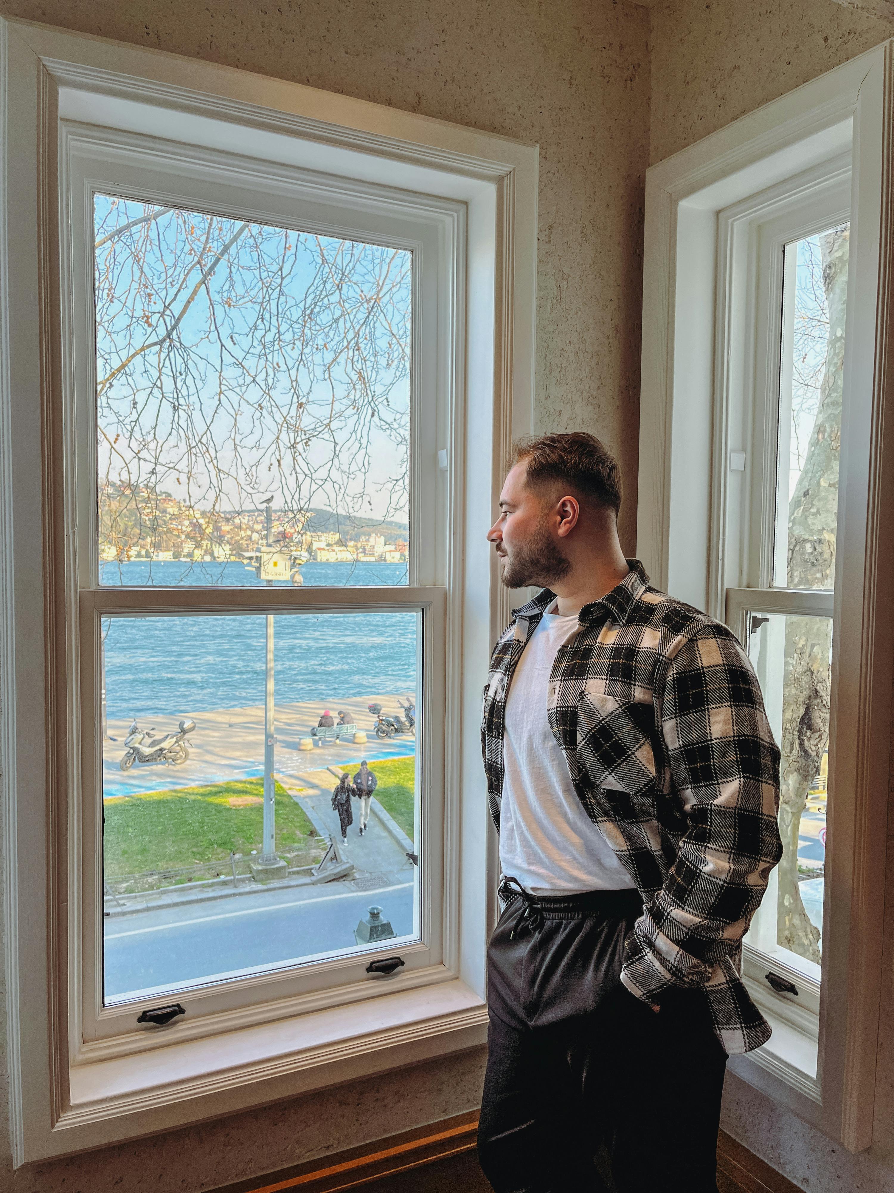 Man in Checked Shirt and Jogging Pants Posing by Window · Free Stock Photo