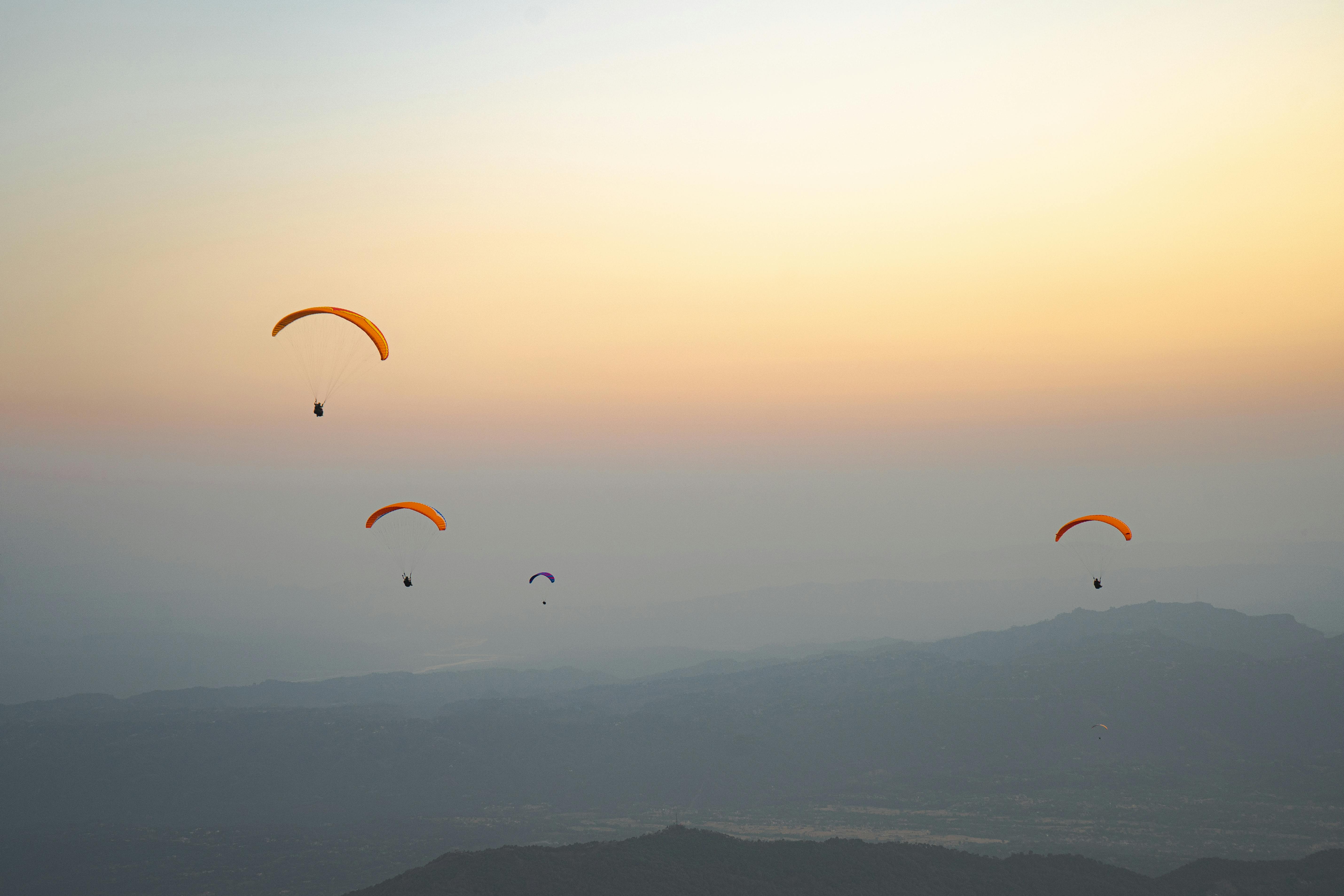 People Parachuting over Hills at Sunset · Free Stock Photo