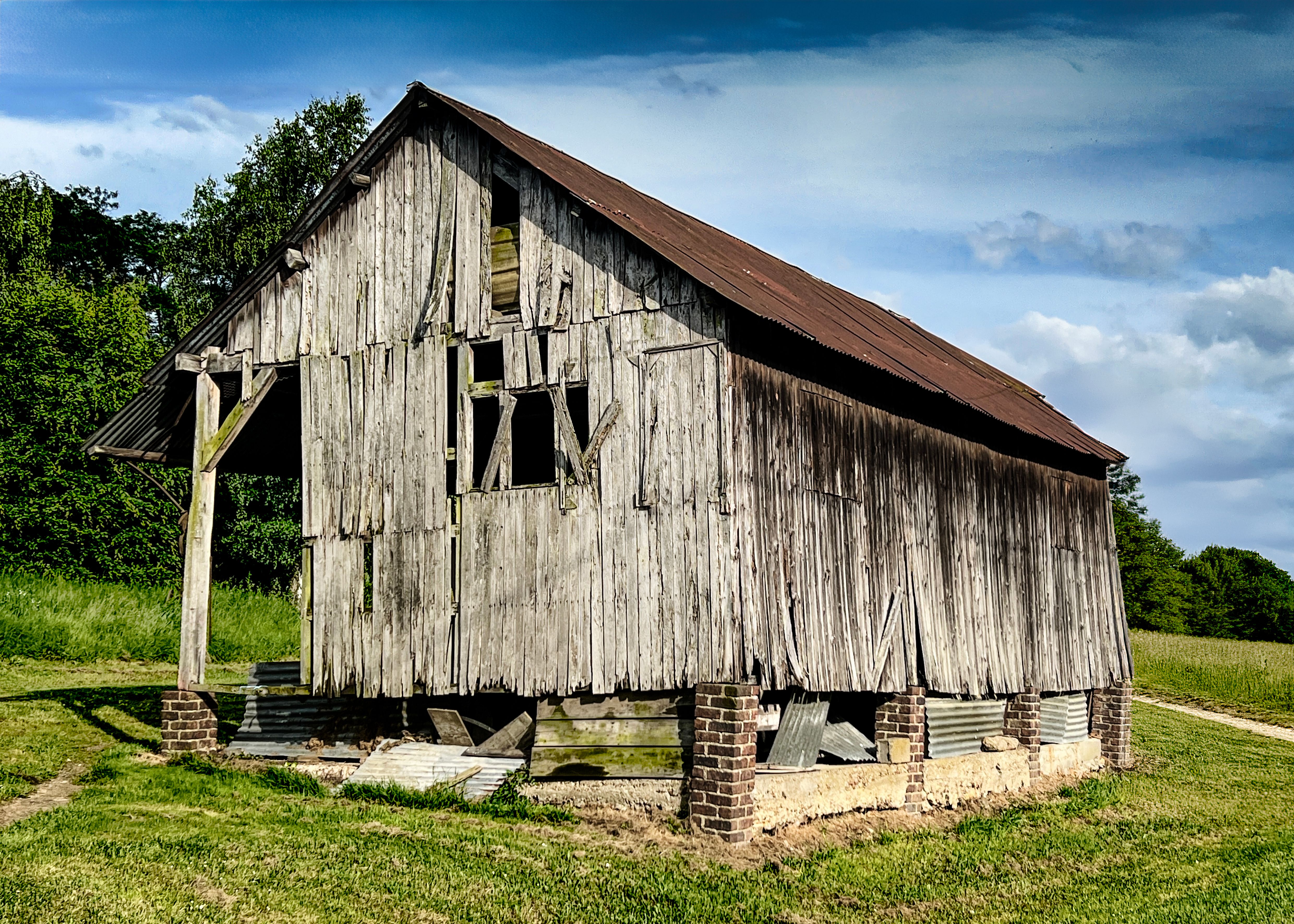 An old barn with a broken roof and a broken door · Free Stock Photo