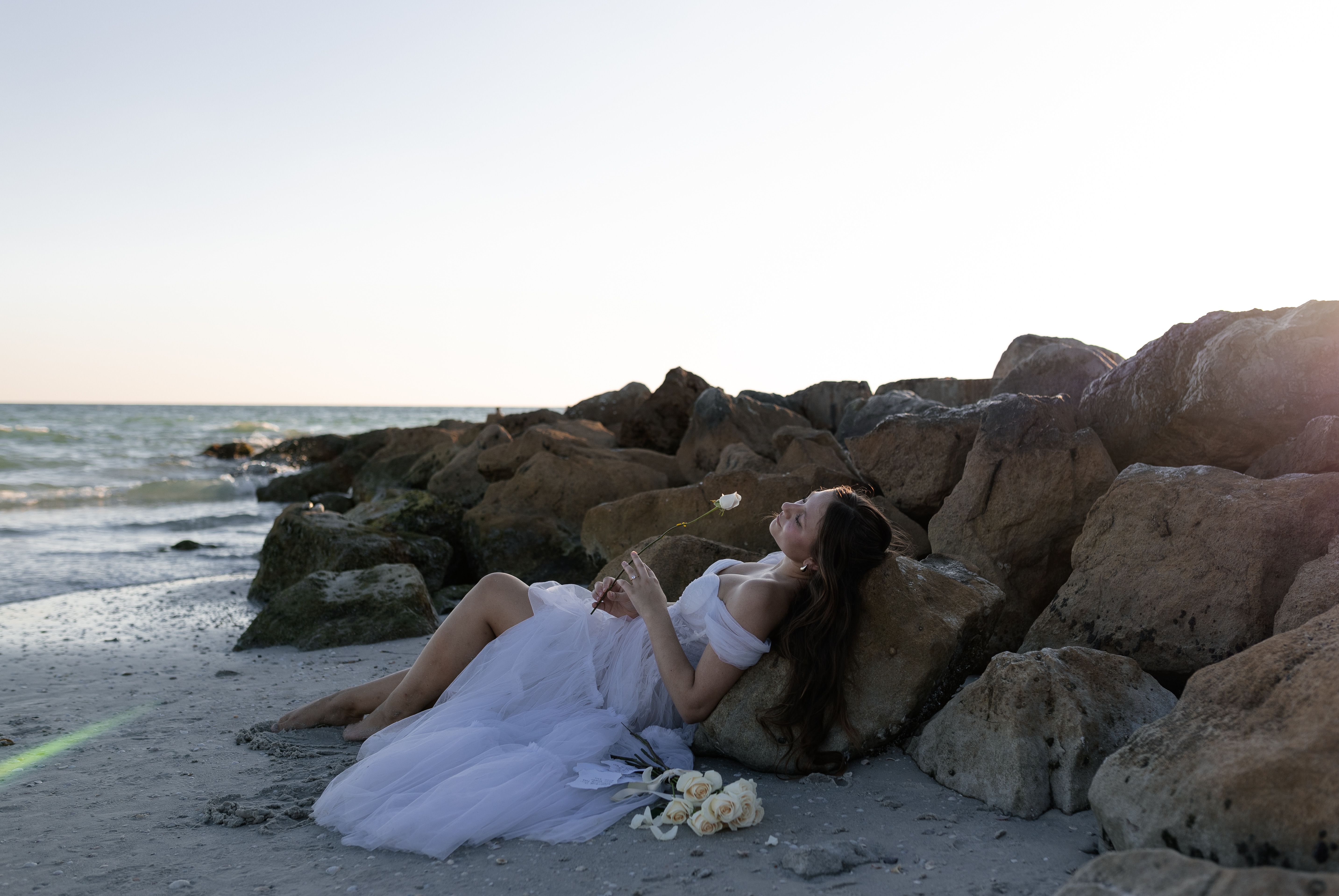 Bride in Wedding Dress Lying Down on Sea Shore · Free Stock Photo