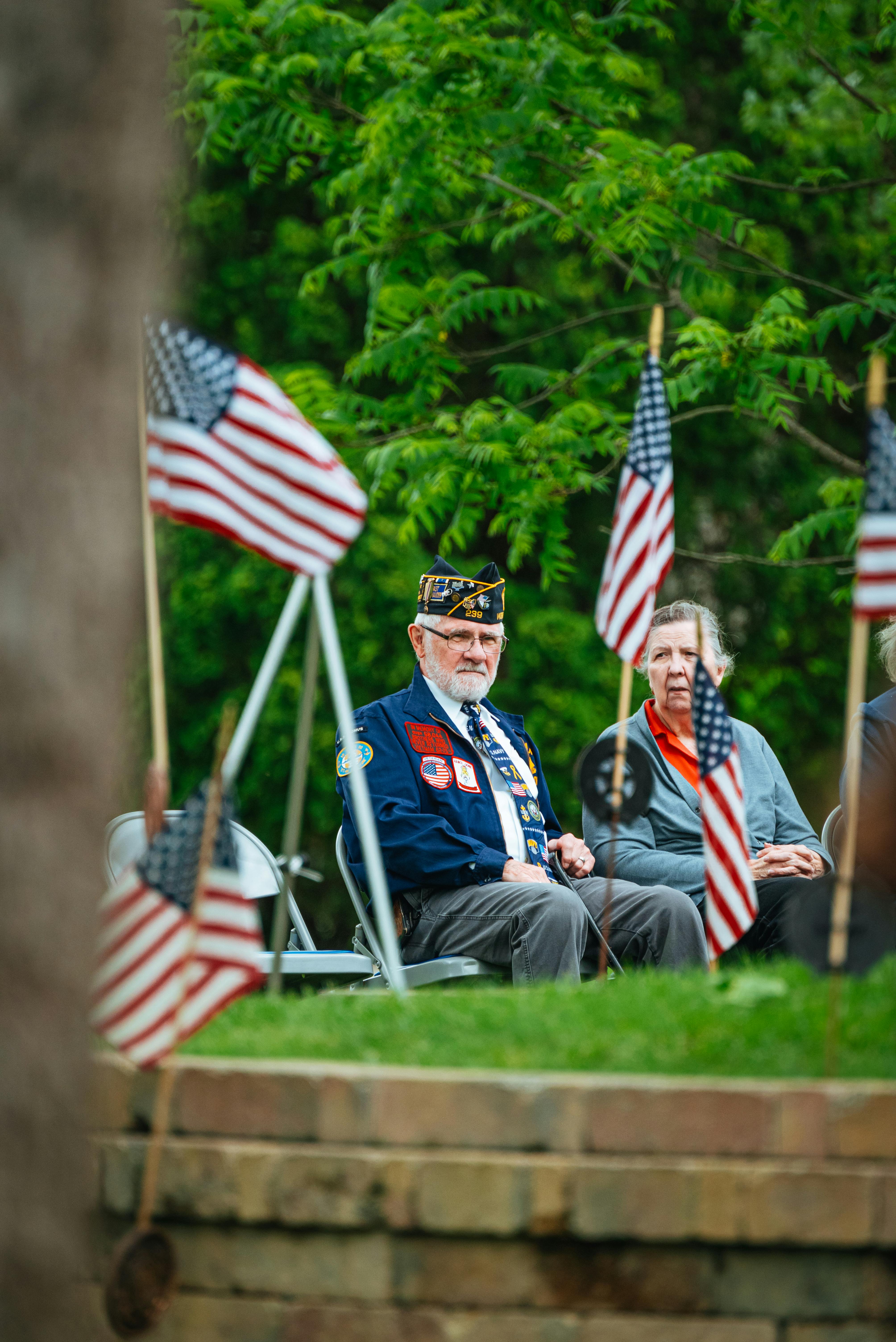 Man in Uniform and Woman Sitting at Cemetery with Flags of the USA ...