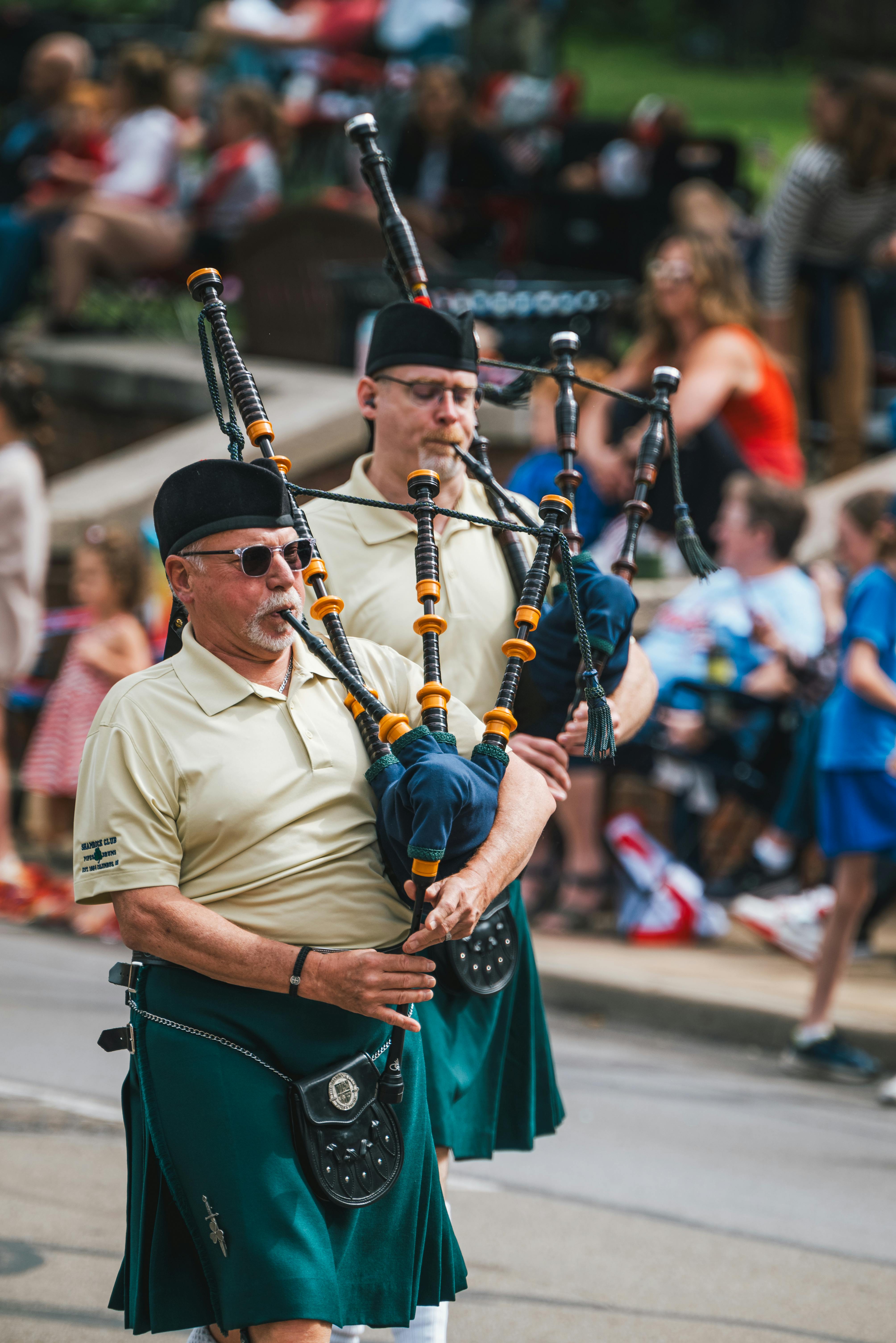 Two men in kilts playing bagpipes in a parade · Free Stock Photo