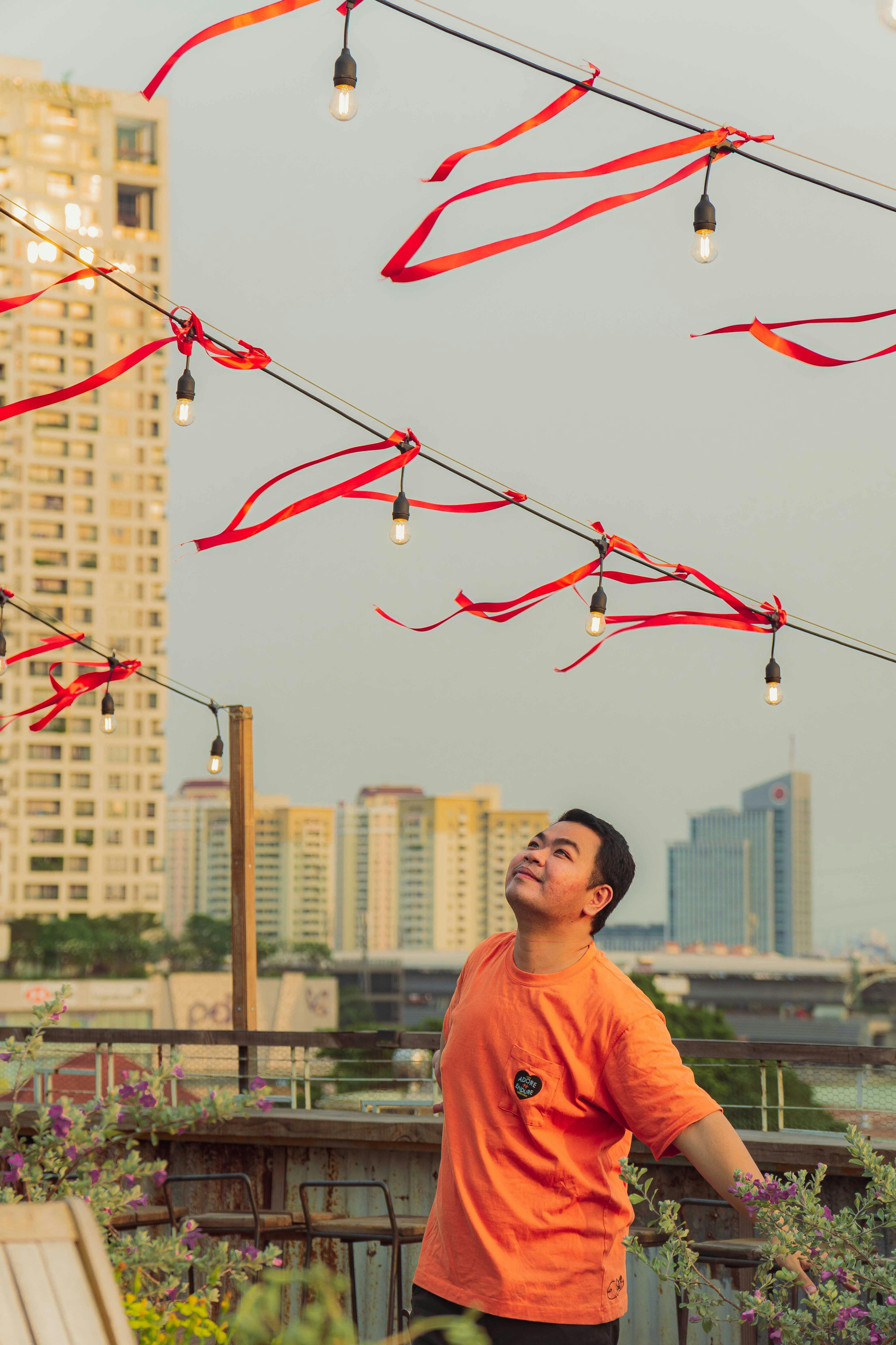 Smiling Man Standing under Light Bulbs and Pennants · Free Stock Photo