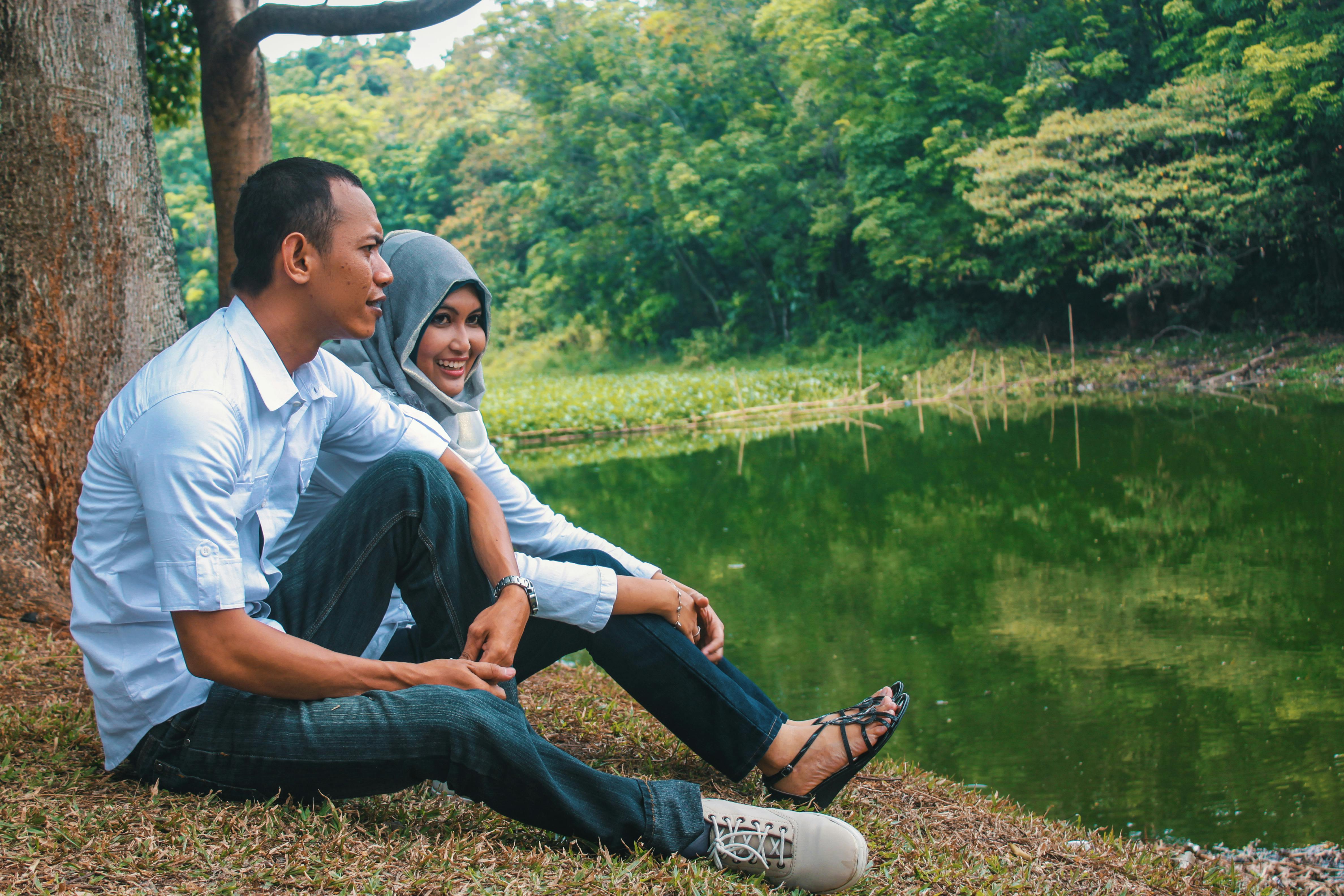 Man and Woman Relaxing over Lake · Free Stock Photo
