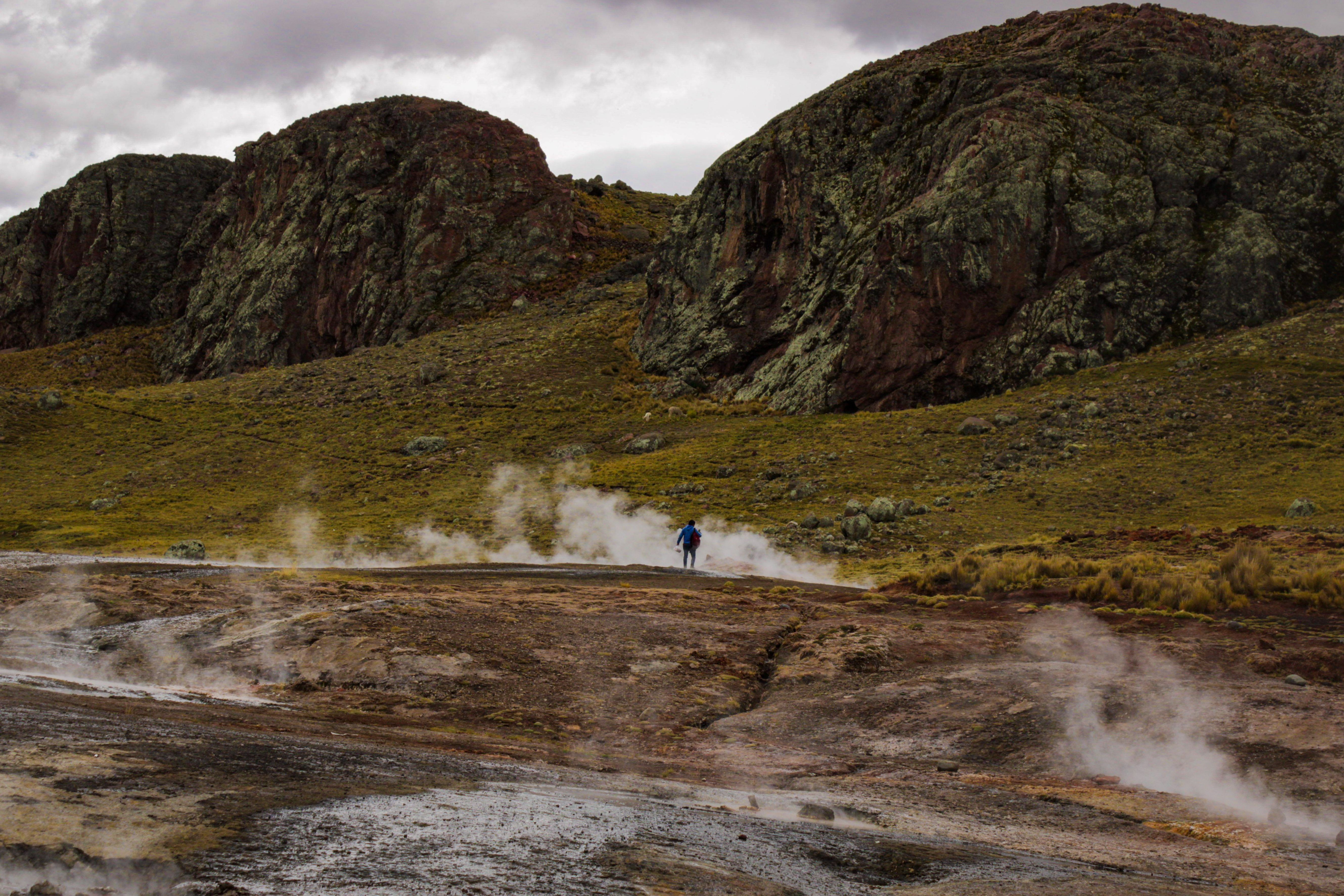 A person walking through a field with steam coming out of the ground ...