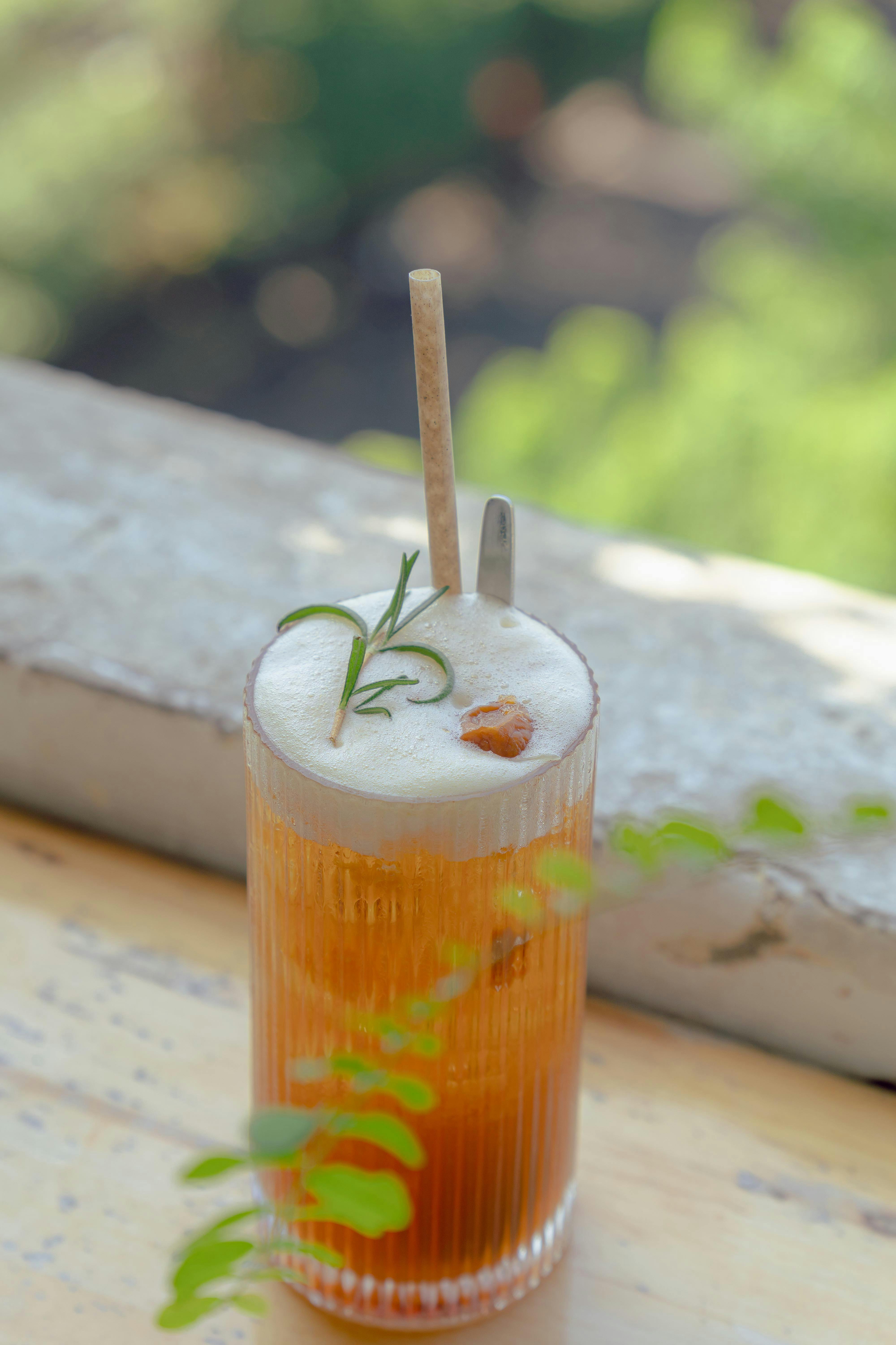 A drink with a straw and a sprig of rosemary · Free Stock Photo