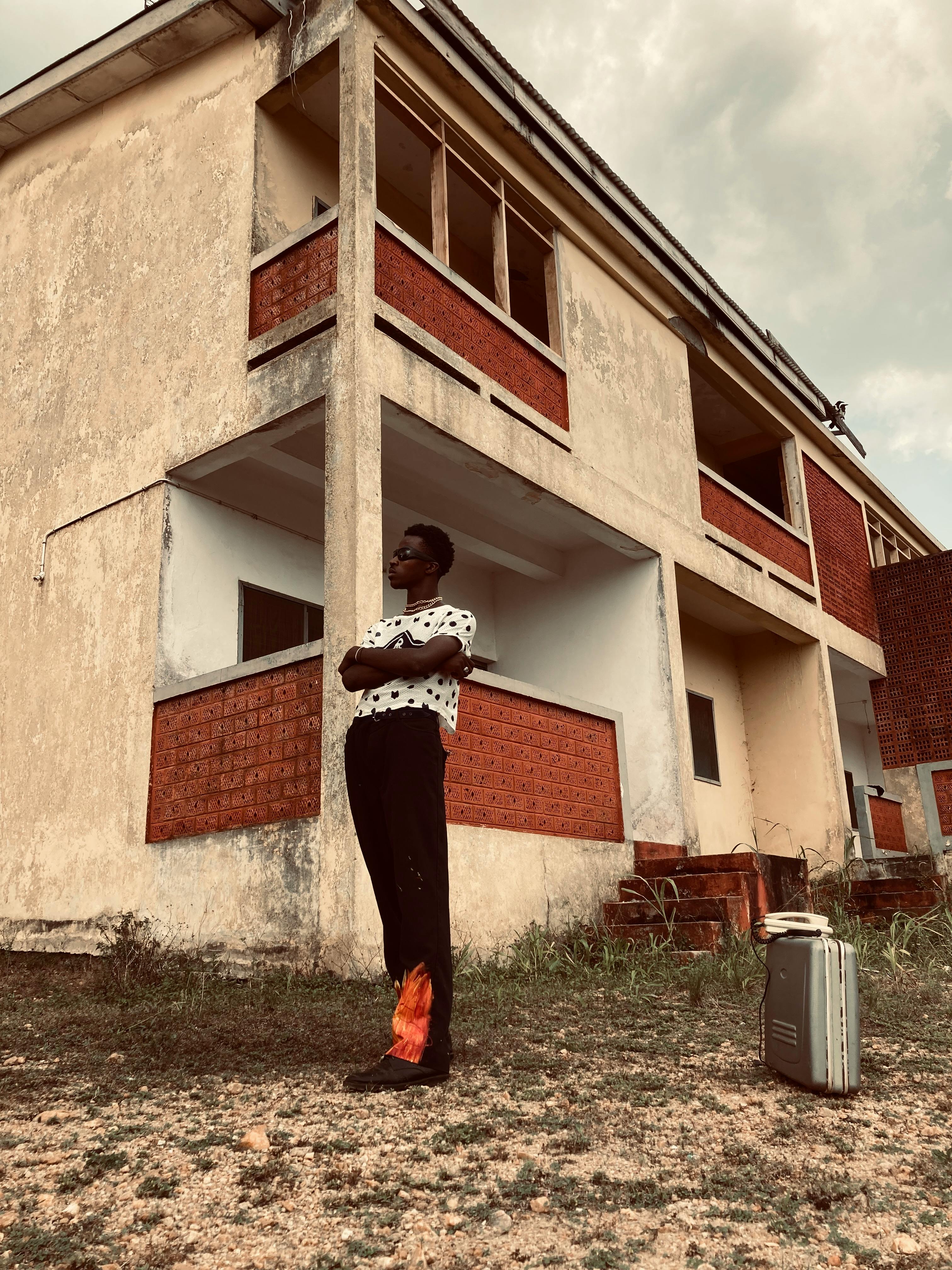 Man Standing with Arms Crossed next to House in Village · Free Stock Photo