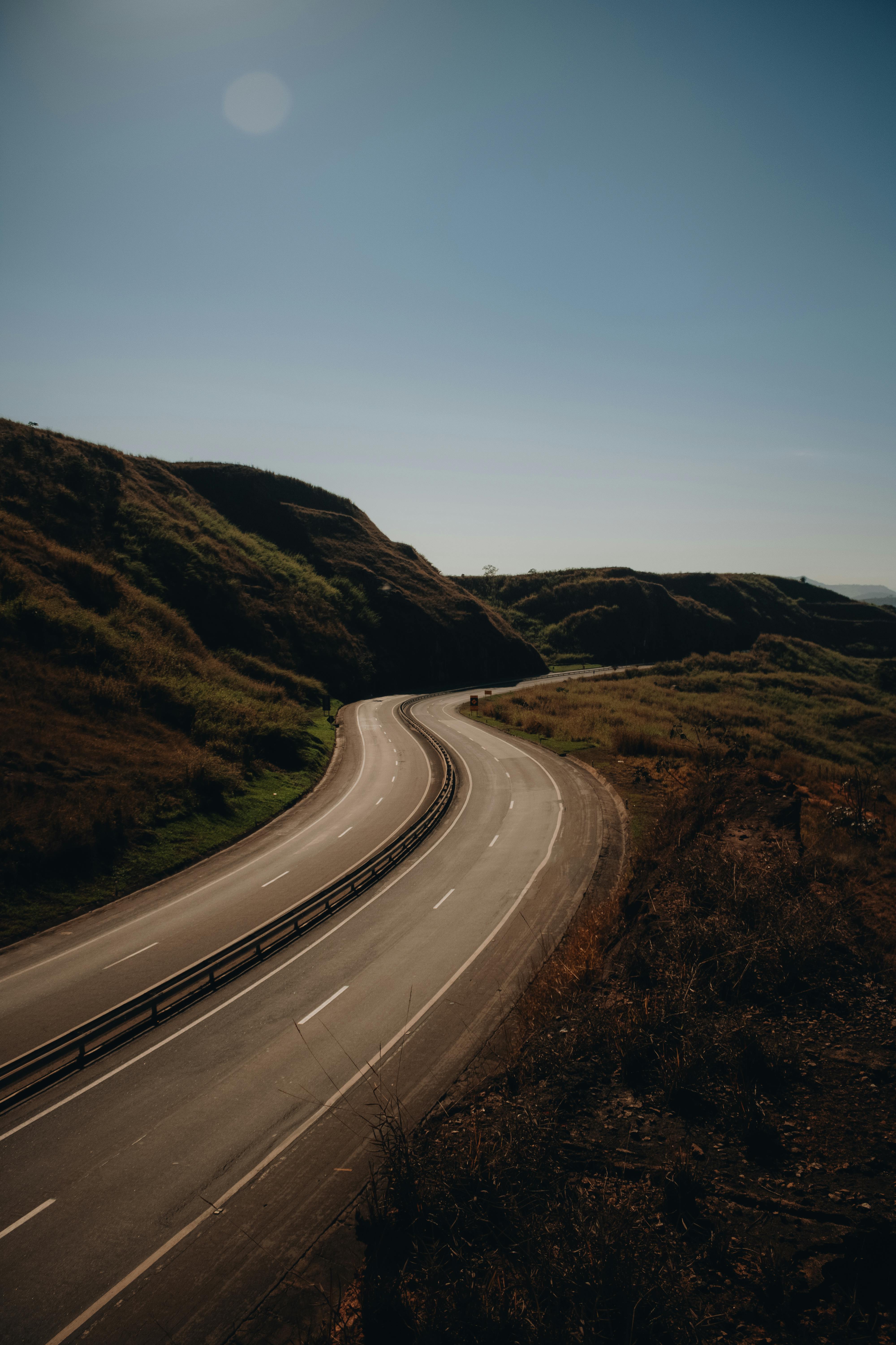 Asphalt road running through hilly terrain in summer · Free Stock Photo