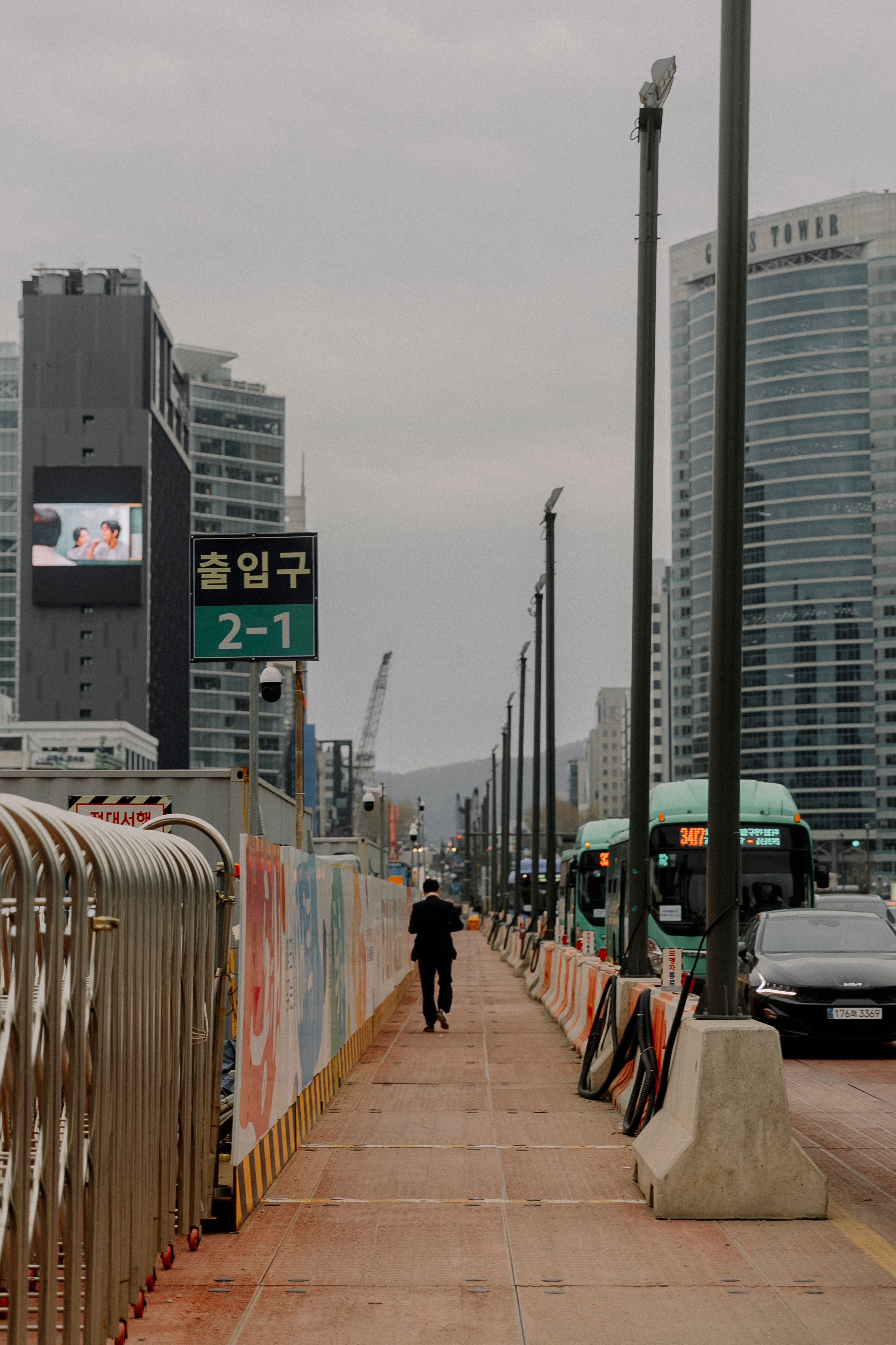 A person walking down a sidewalk next to a bus · Free Stock Photo