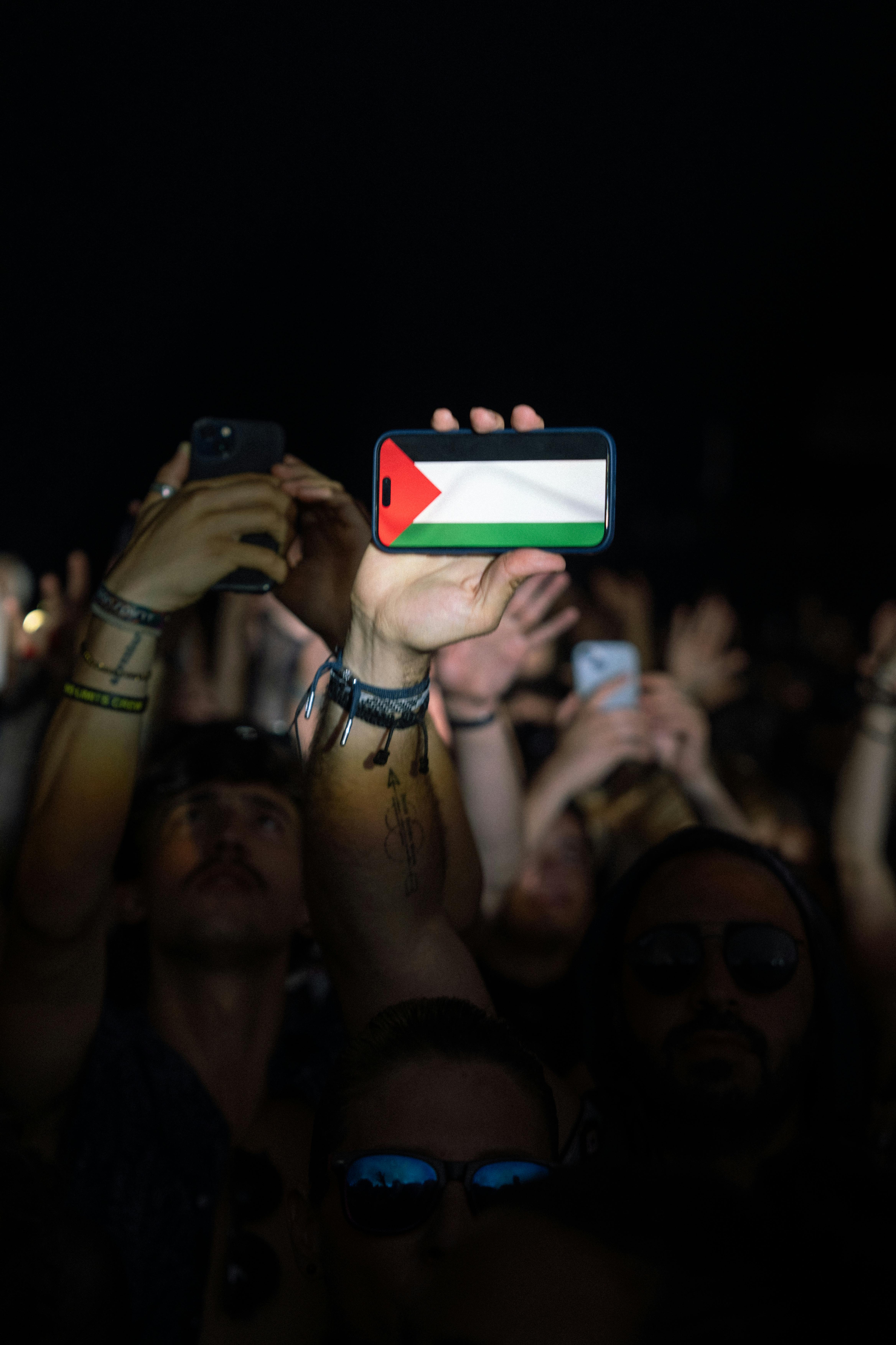 A person holding up a cell phone with the flag of palestine · Free ...