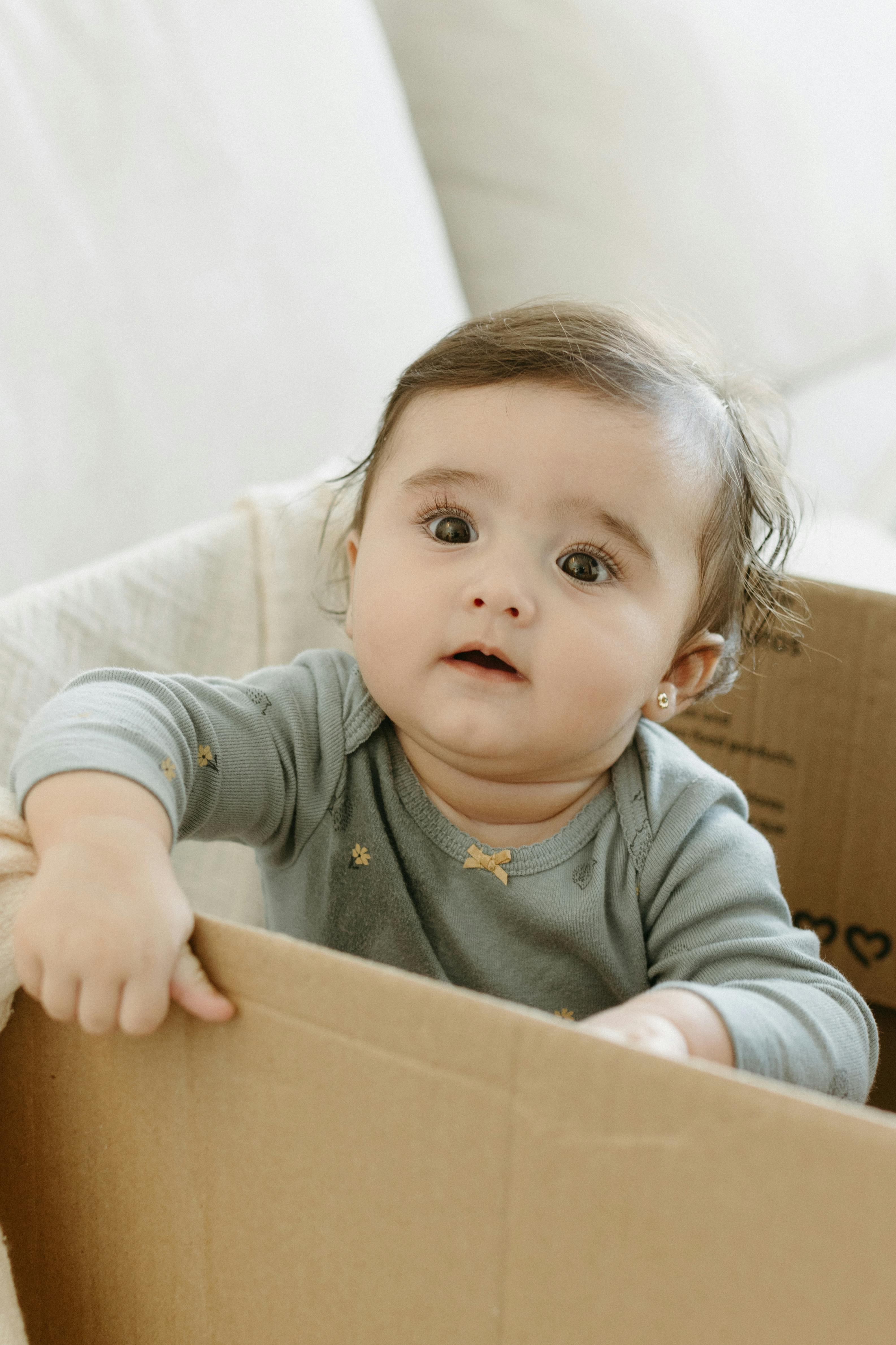 Baby Girl Sitting in Cardboard Box · Free Stock Photo