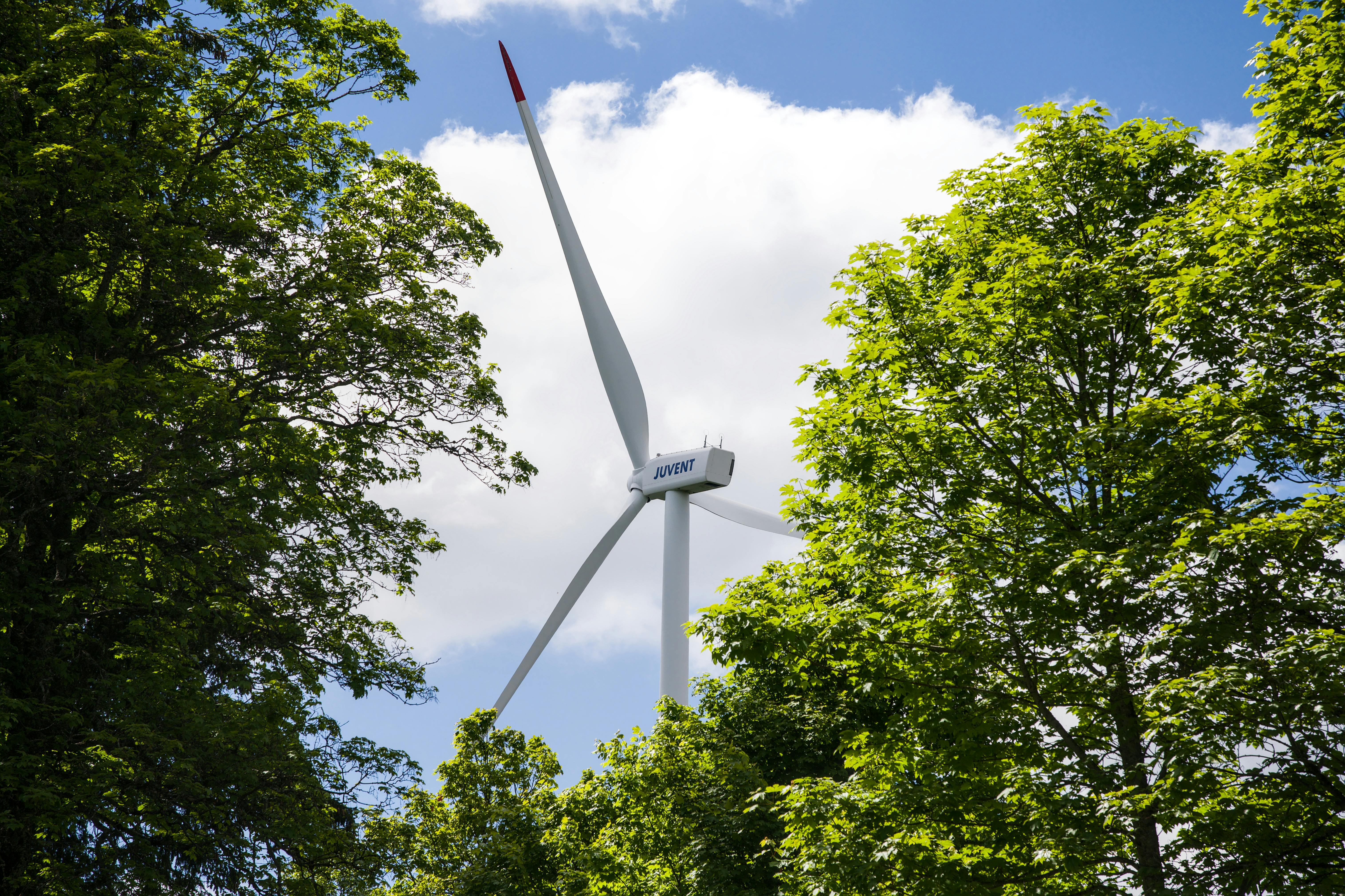 A wind turbine in the woods with trees · Free Stock Photo