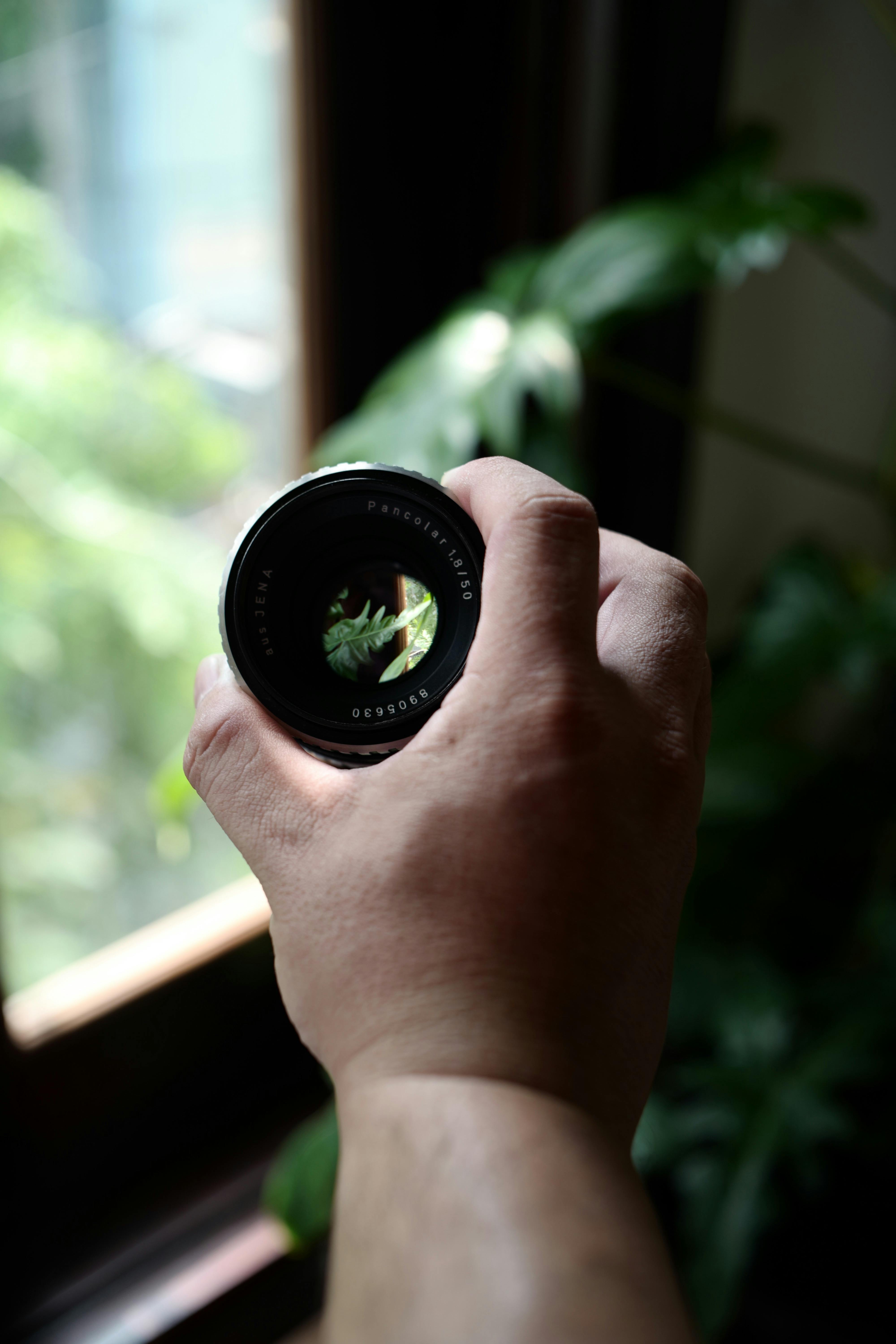 Person Hand Holding Lens of Camera · Free Stock Photo